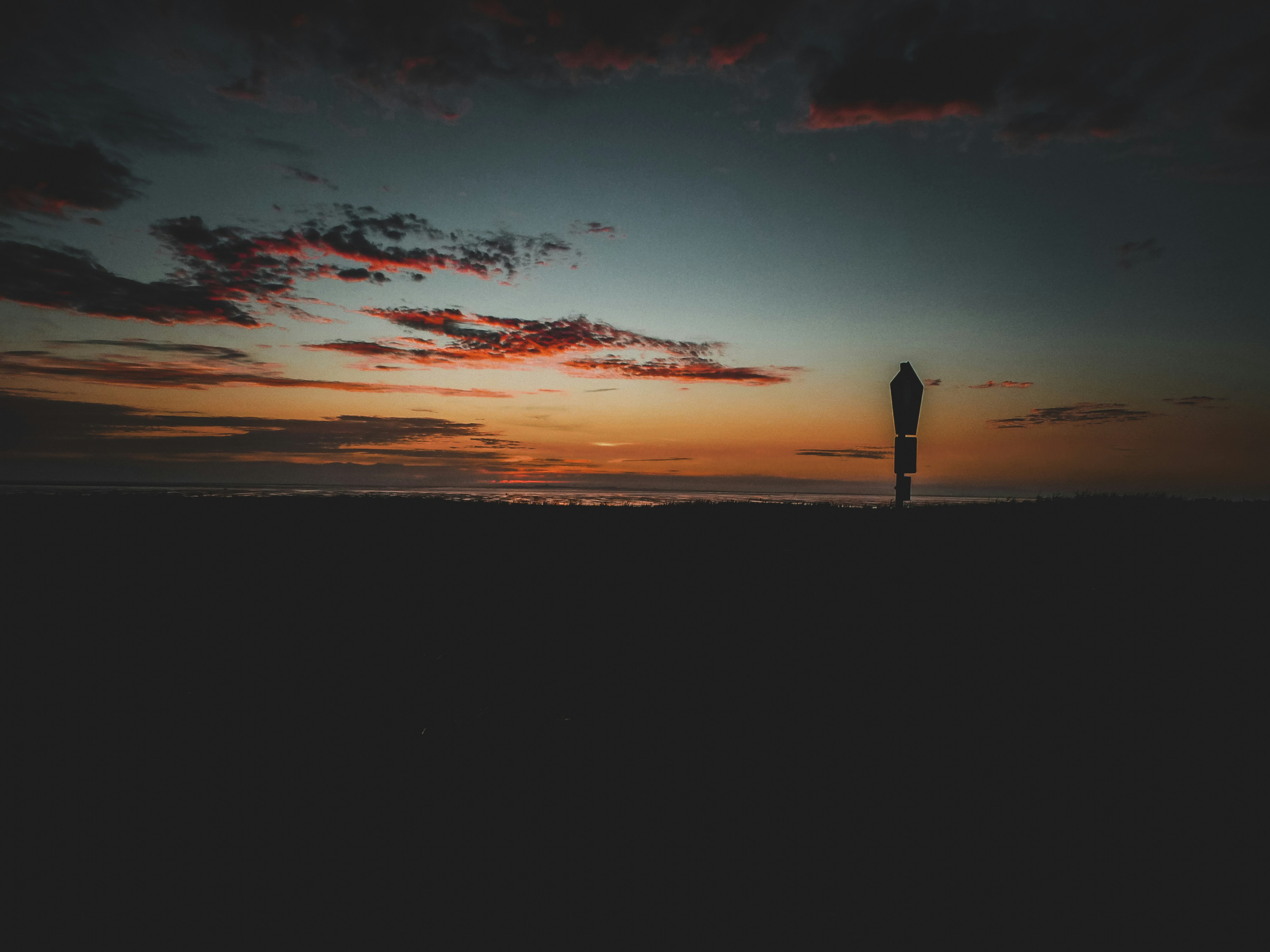 Silhouette at Dusk: Lighthouse Against a Fiery Horizon