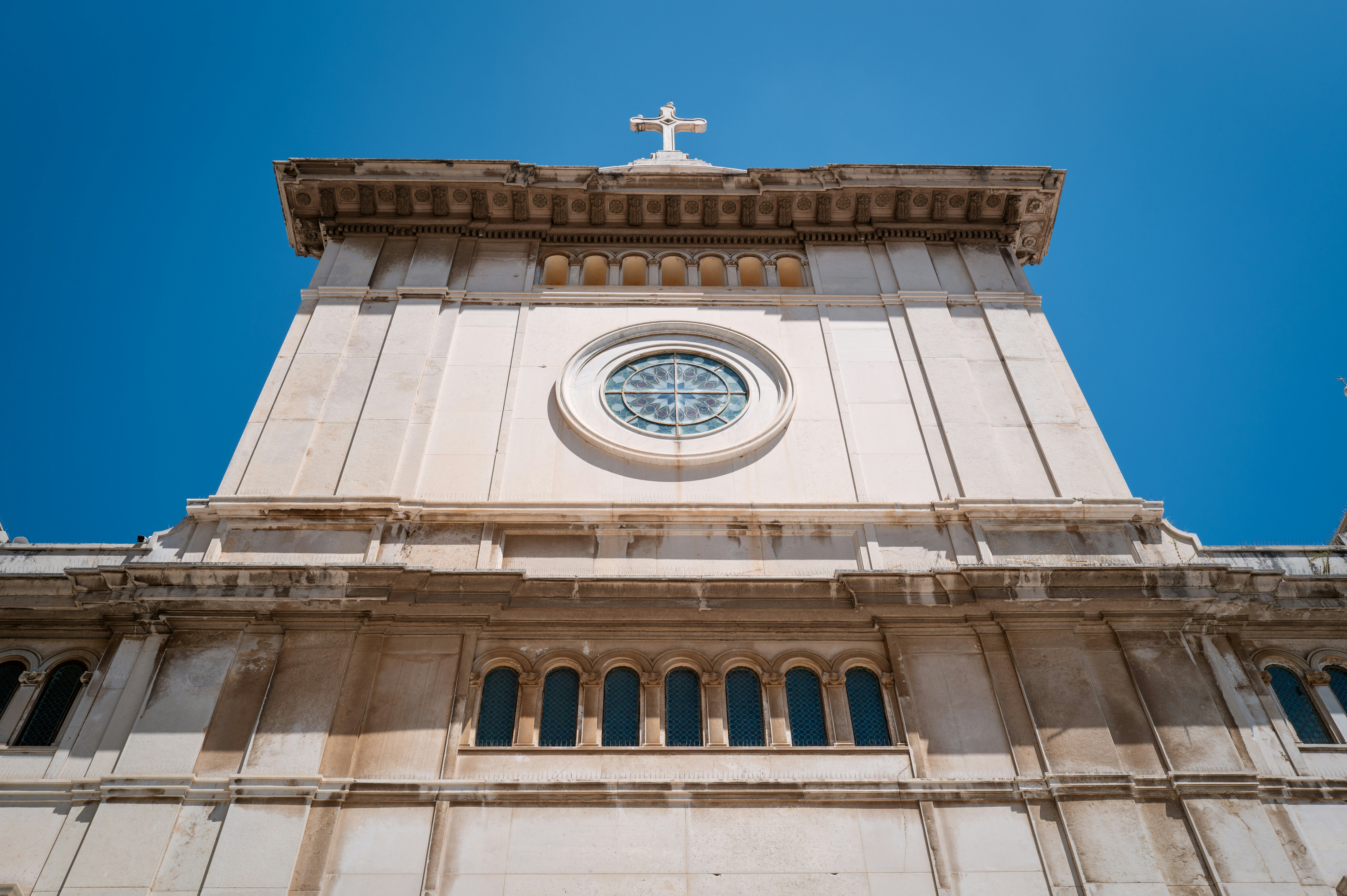 White church facade with a cross and round window.