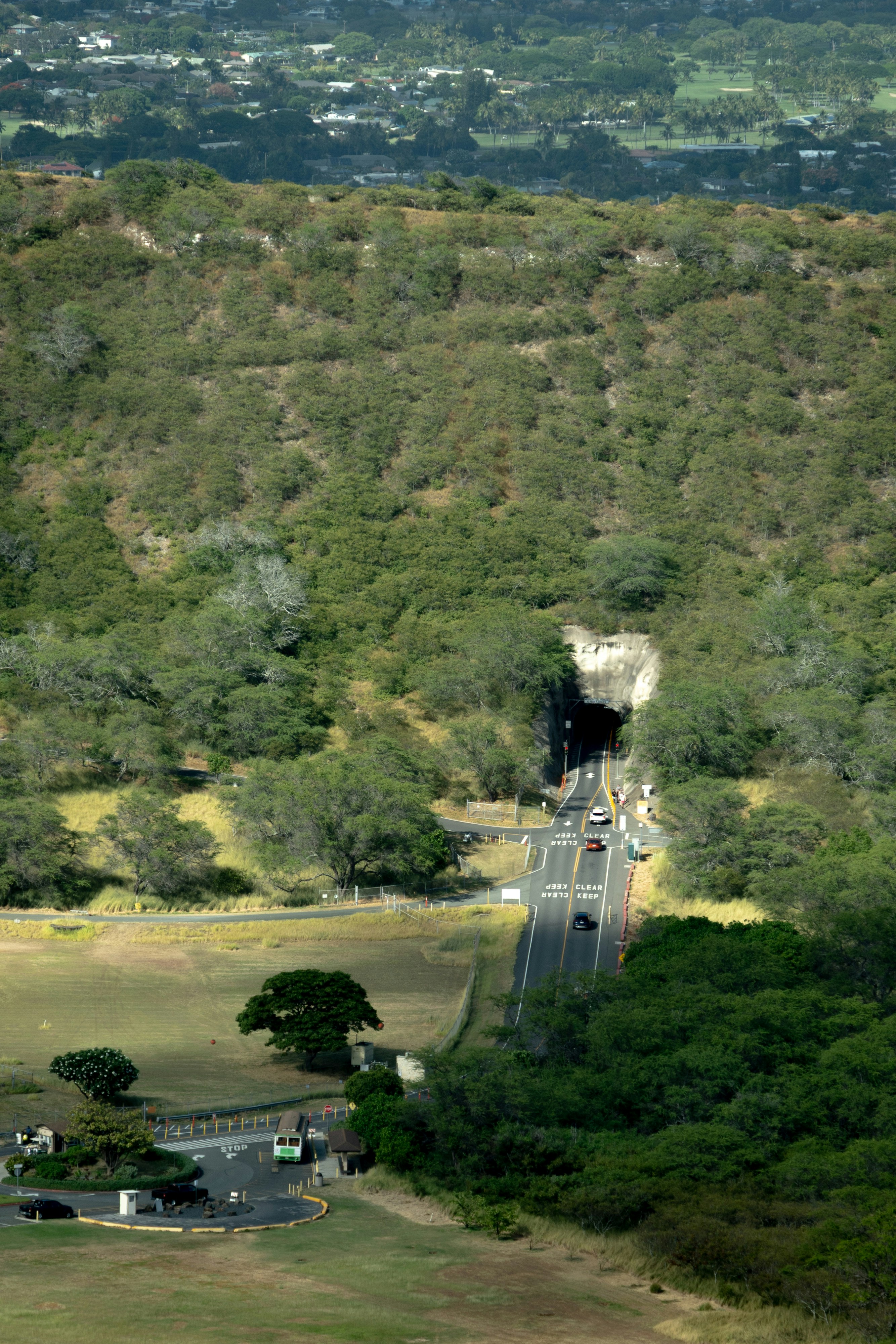 Tunnel Vision: Cars Converge at the Green-Hued Hillside Pass