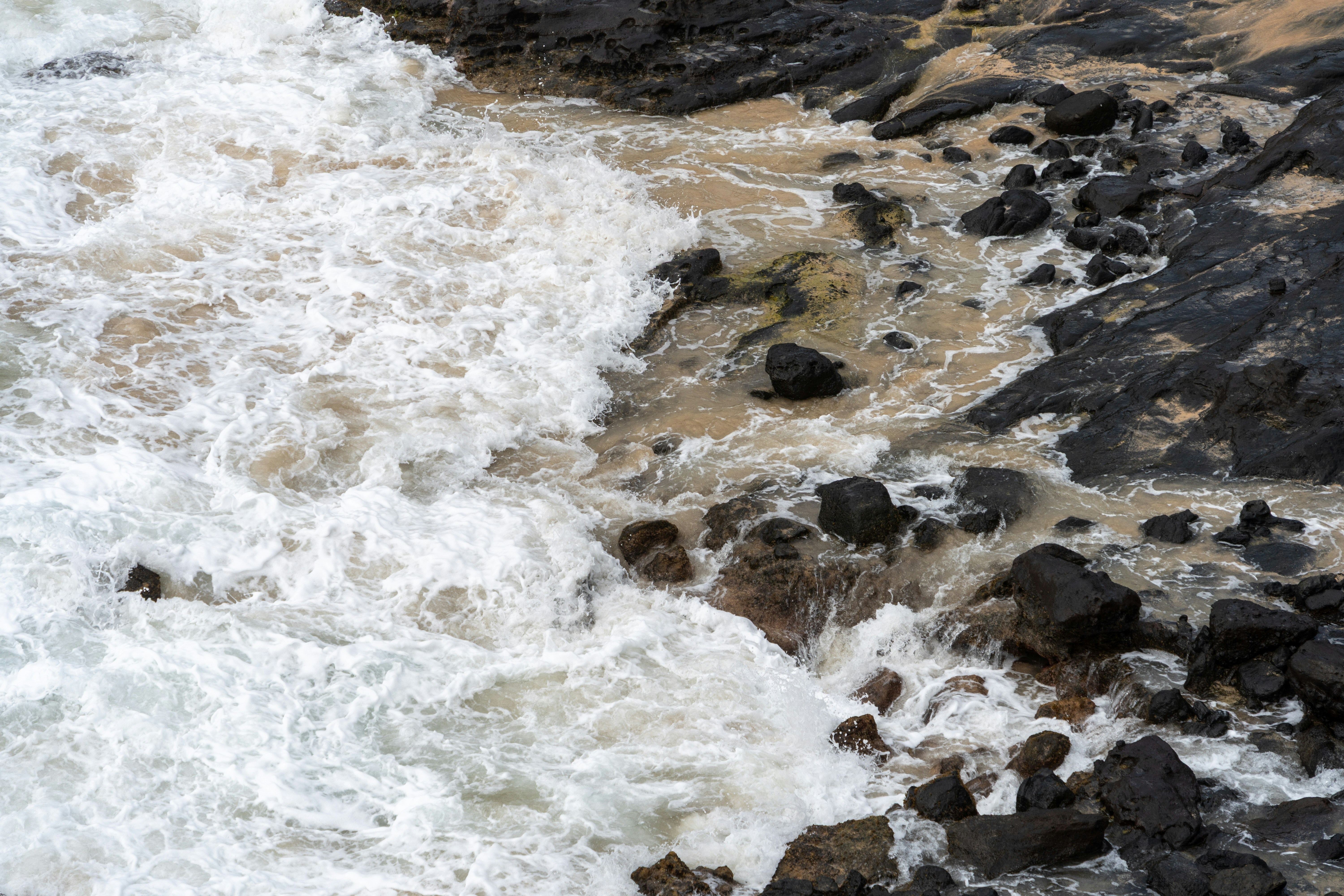 Foamy Breakers Crest Over Darkened Rocks