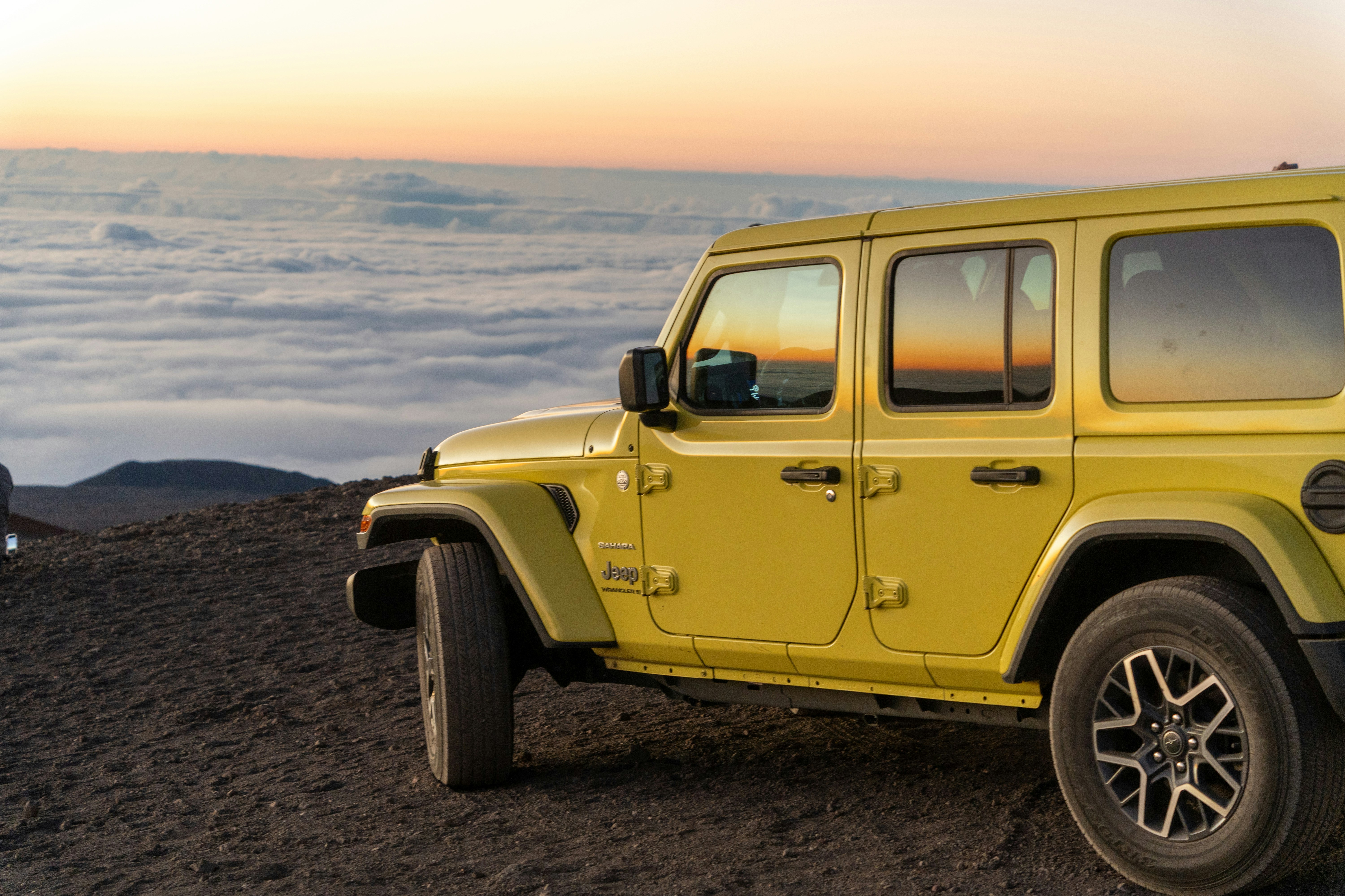 Sunlit Yellow Jeep on a Volcanic Ridge at Sunset