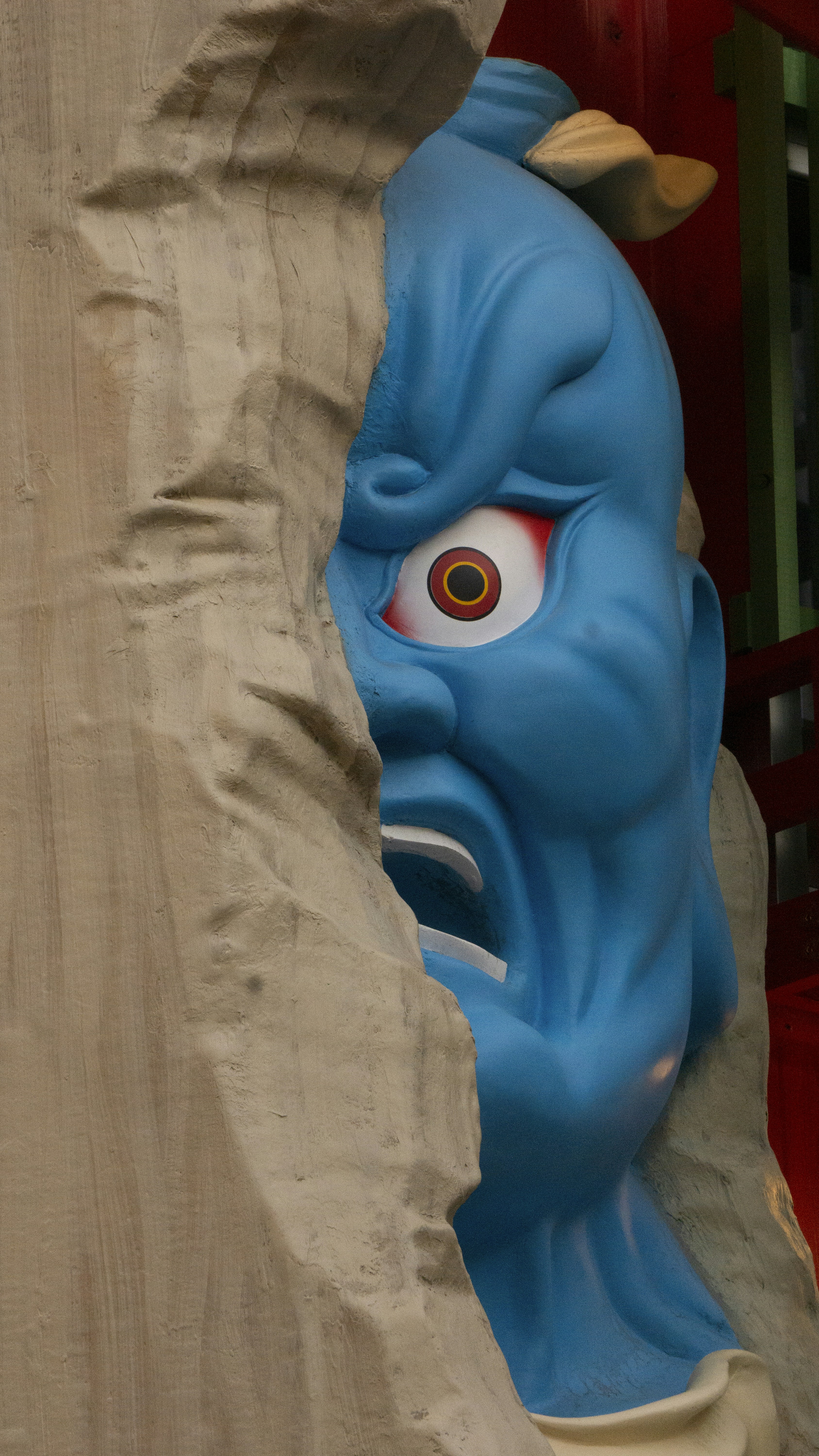 Giant Blue Head Emerging from a Cracked Rock Wall