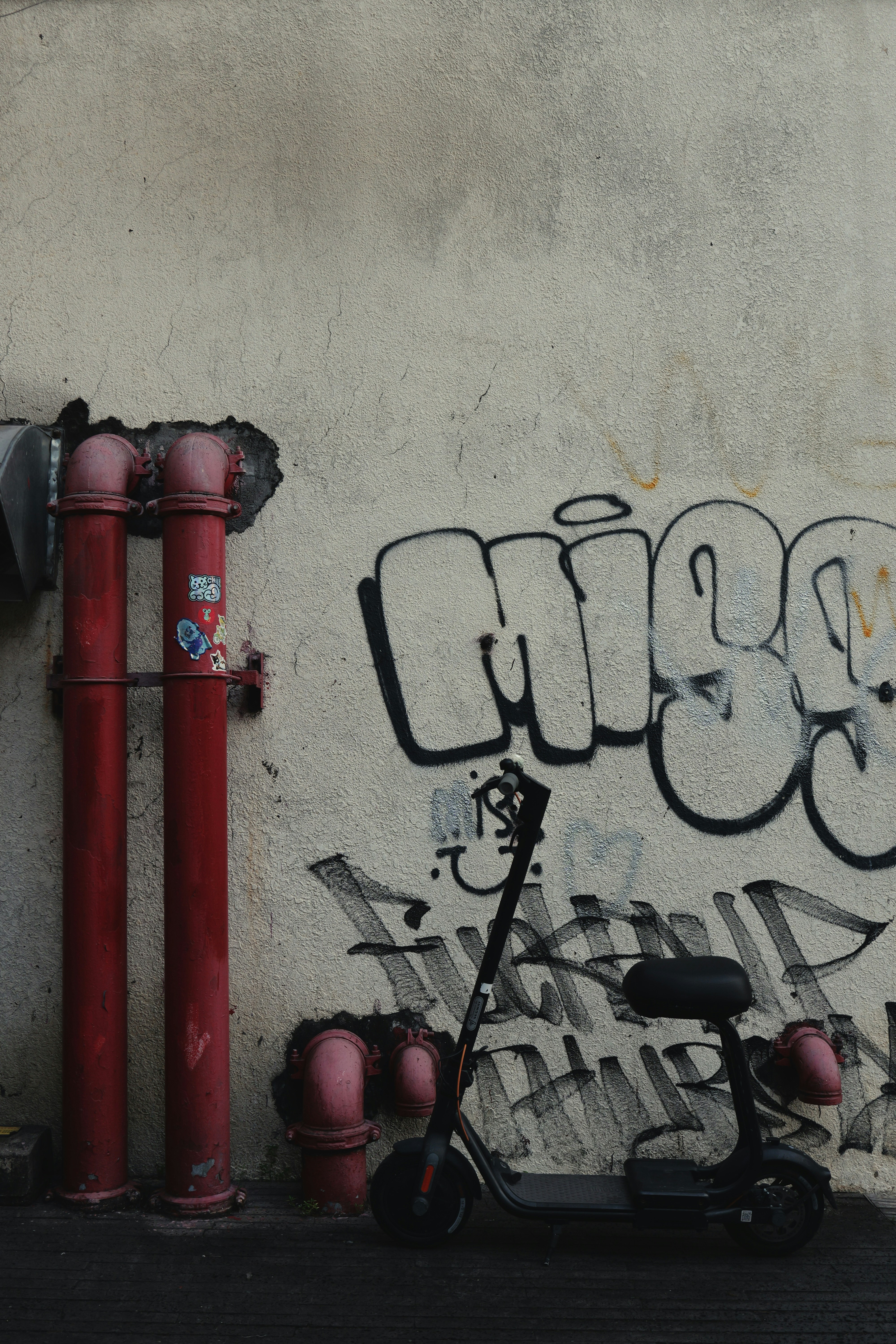 Urban Glide: A Scooter Resting by Graffiti and Pipes
