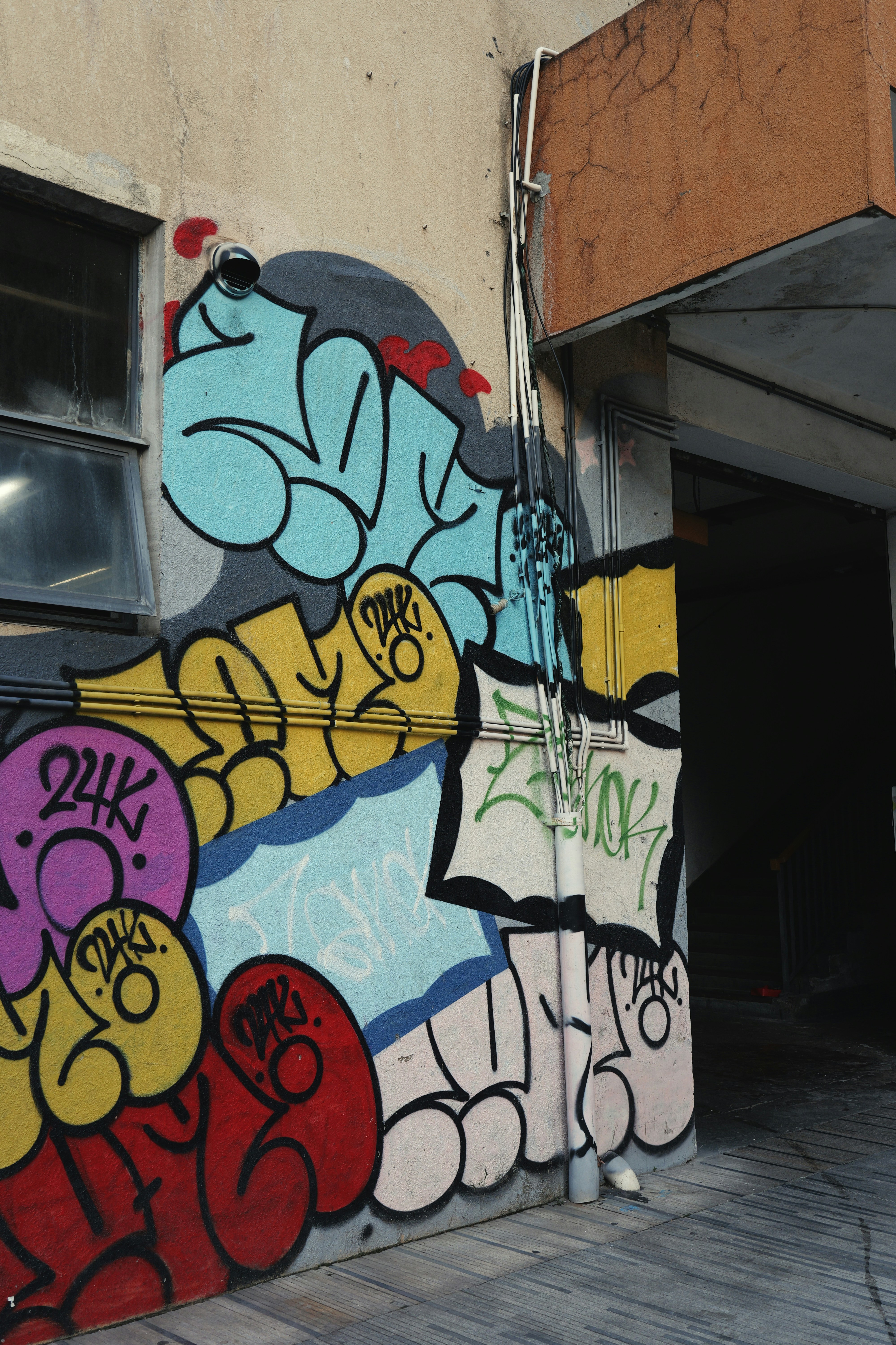 Vivid Graffiti Corner: Colorful Wall Art at a Narrow Alley Entrance