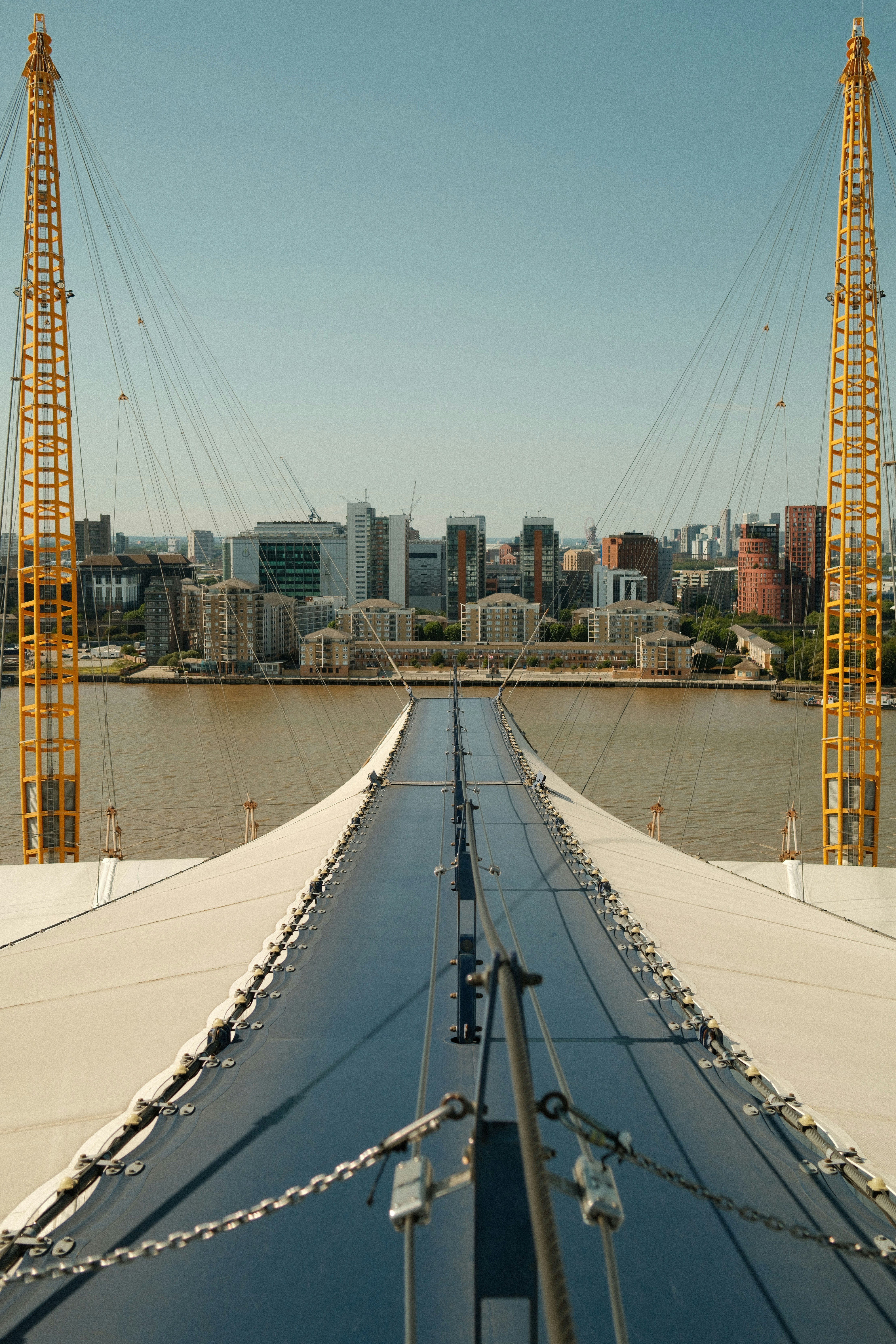 Sailing toward the city: a suspended bridge arches over calm waters