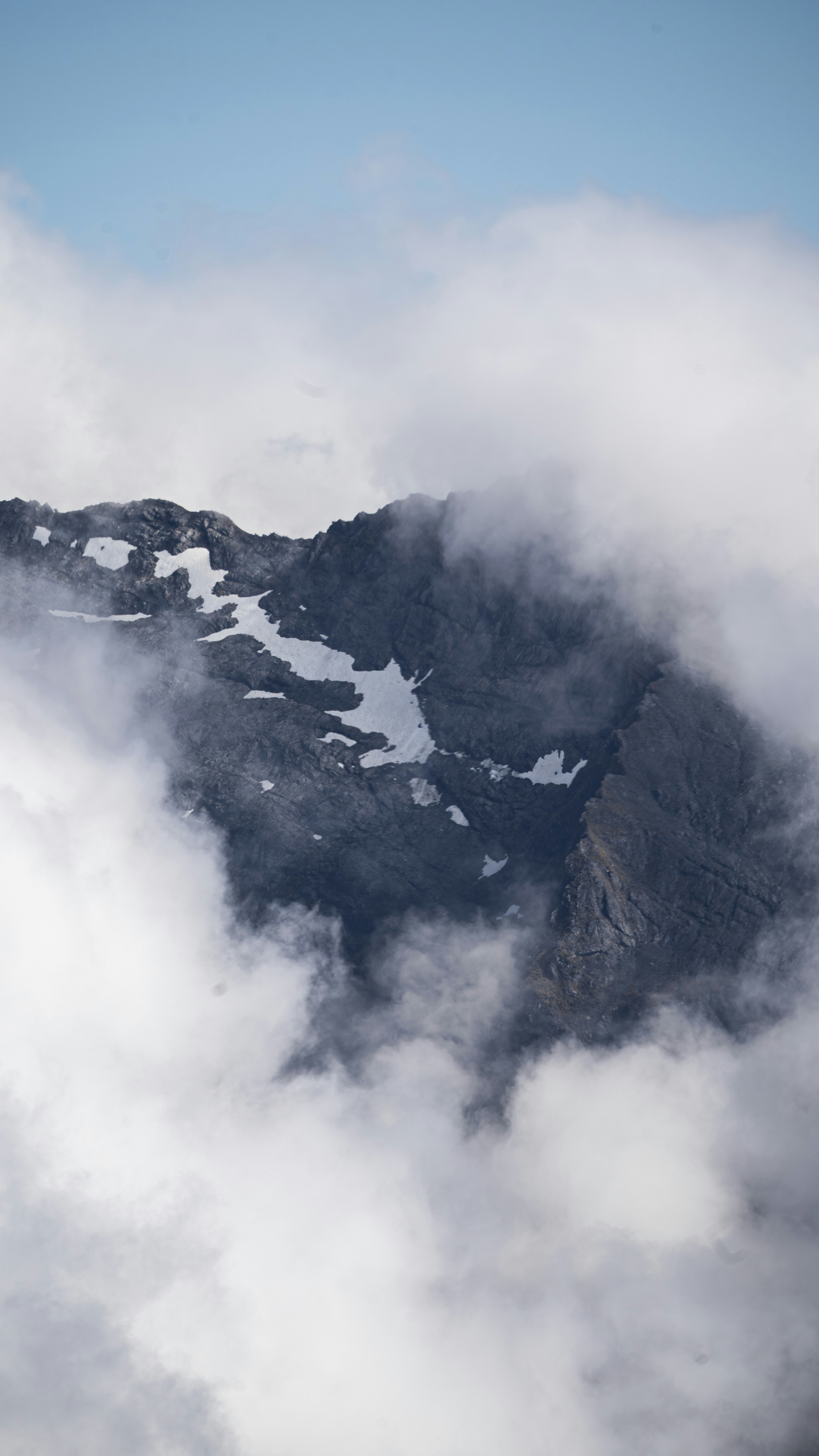 Ridge of Clouds: Snow-tipped Peak Breaking Through