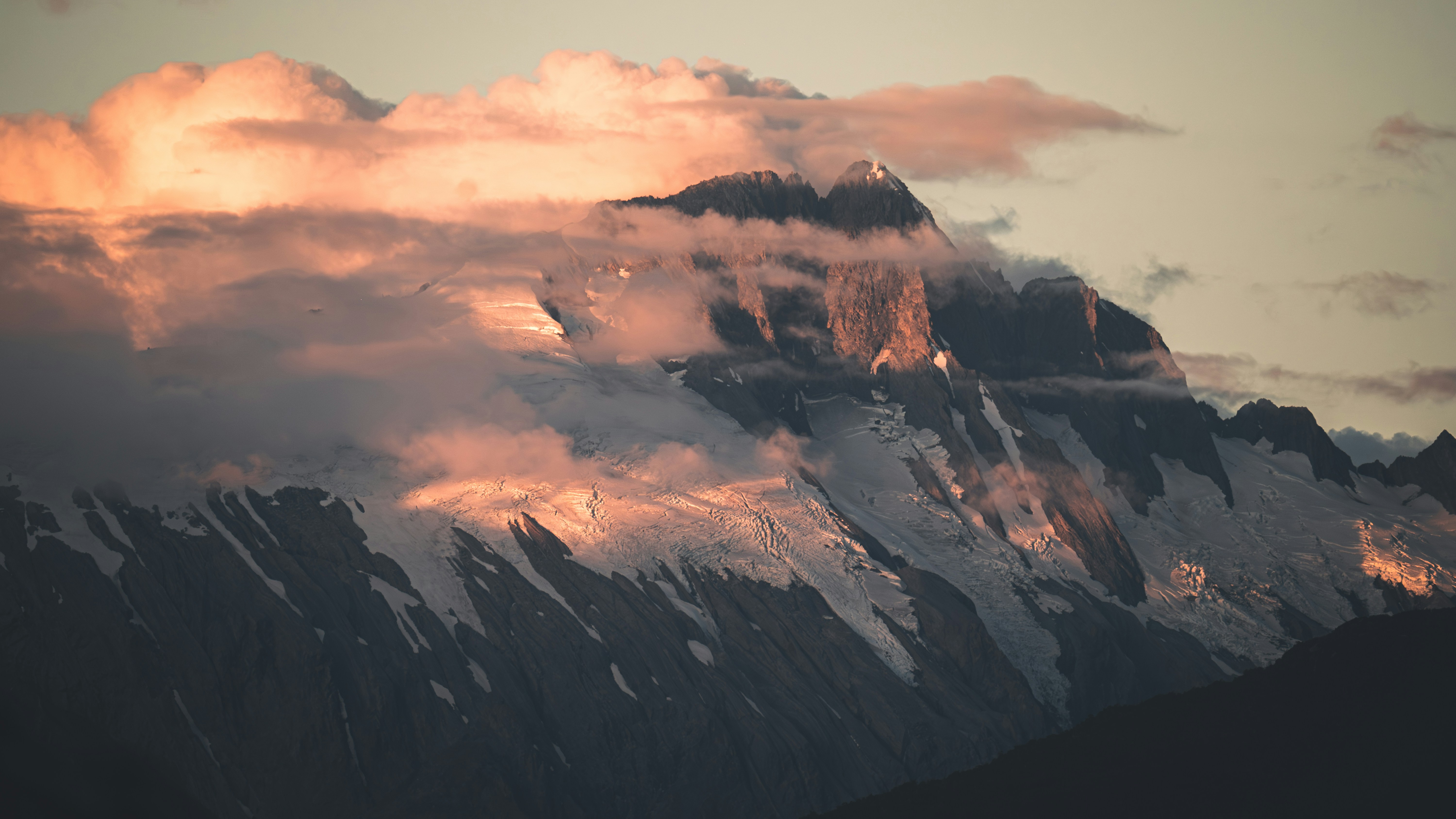 Sunlit Peak Emerges from Coral Clouds at Dusk