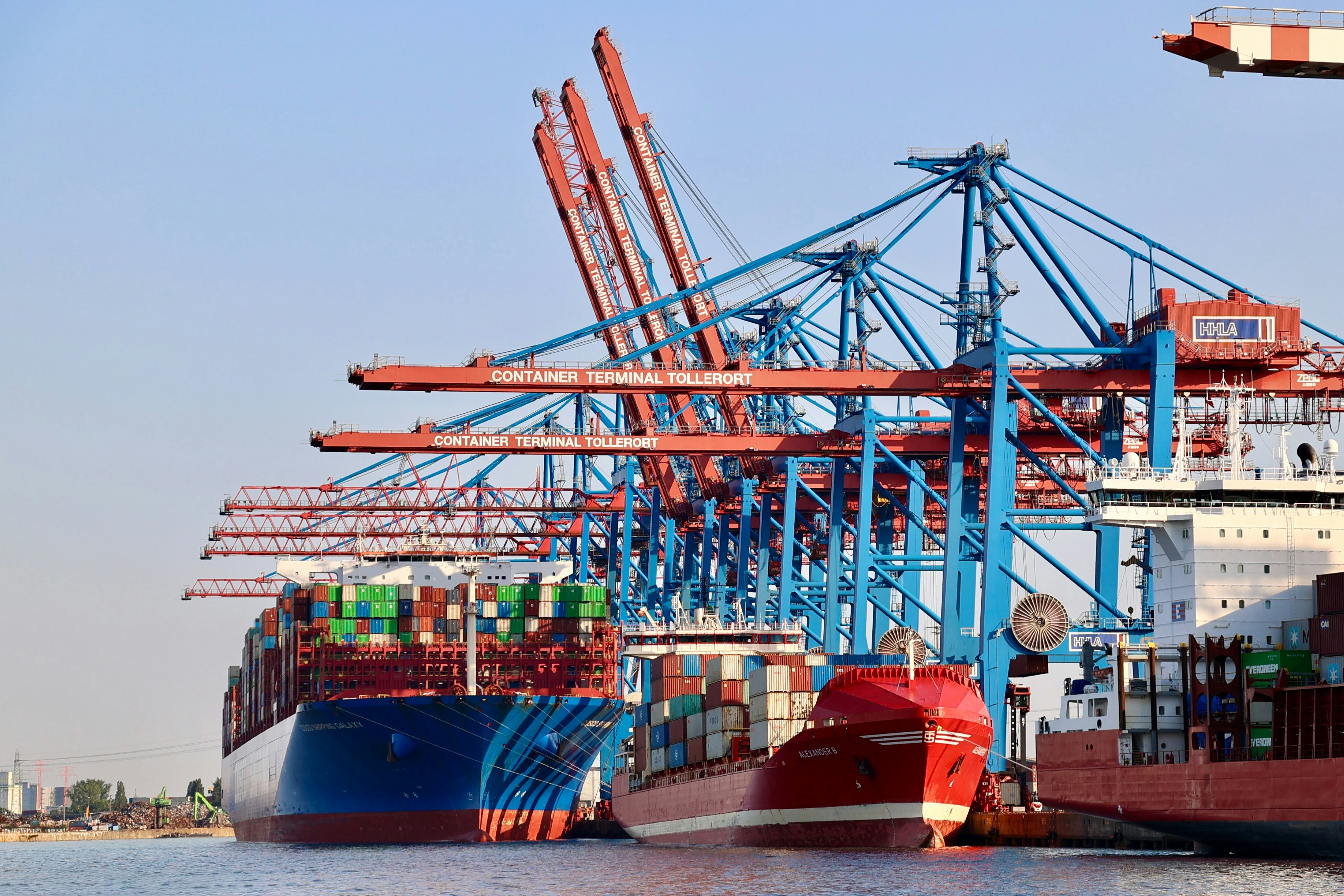 Harbor Giants: Cargo Cranes Stand Watch Over Stacked Vessels