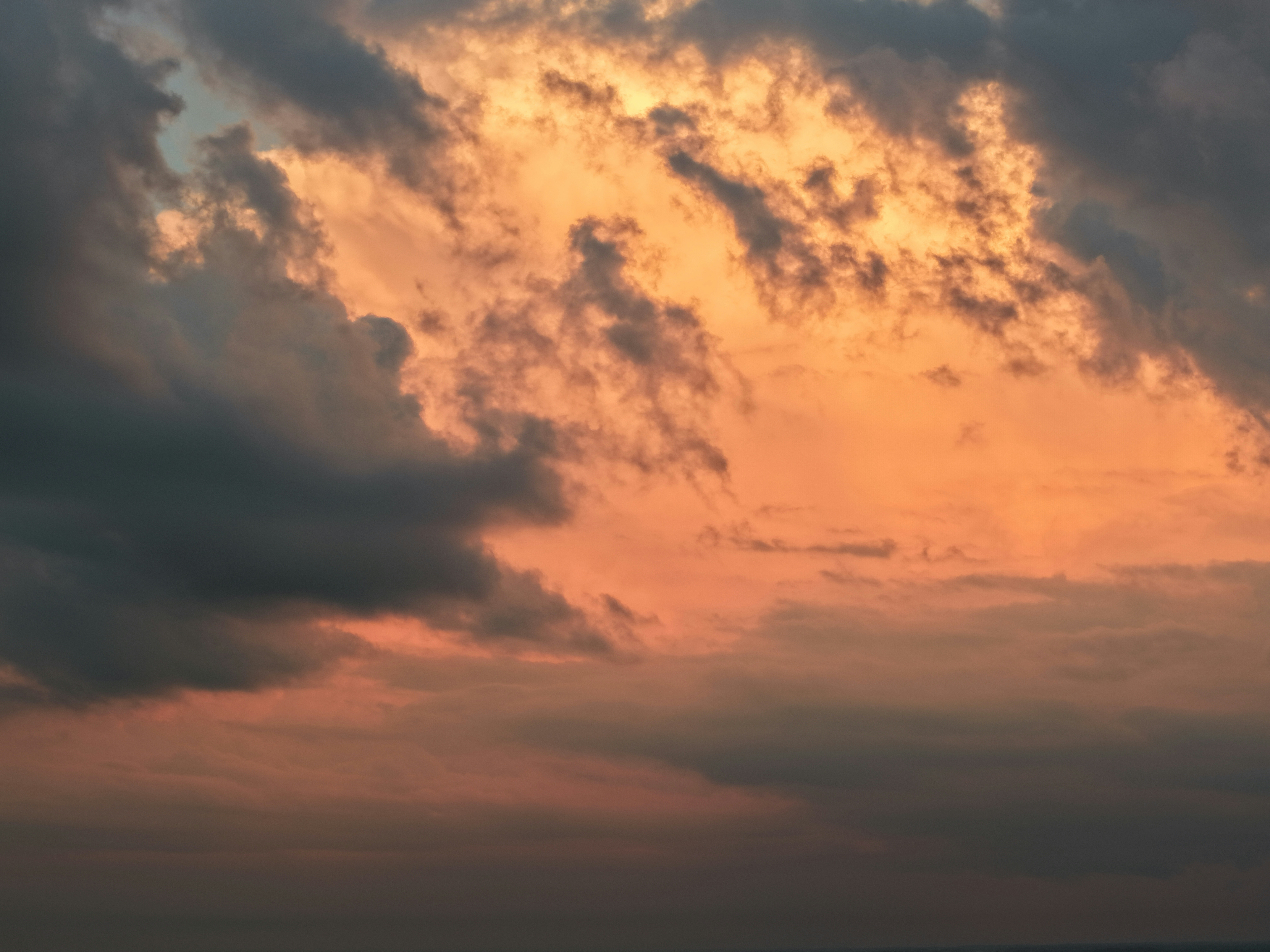 Soft, sweeping sunset clouds with warm copper tones over a calm horizon, conveying tranquil evening mood. The scene emphasizes atmospheric sky texture rather than any foreground subject.