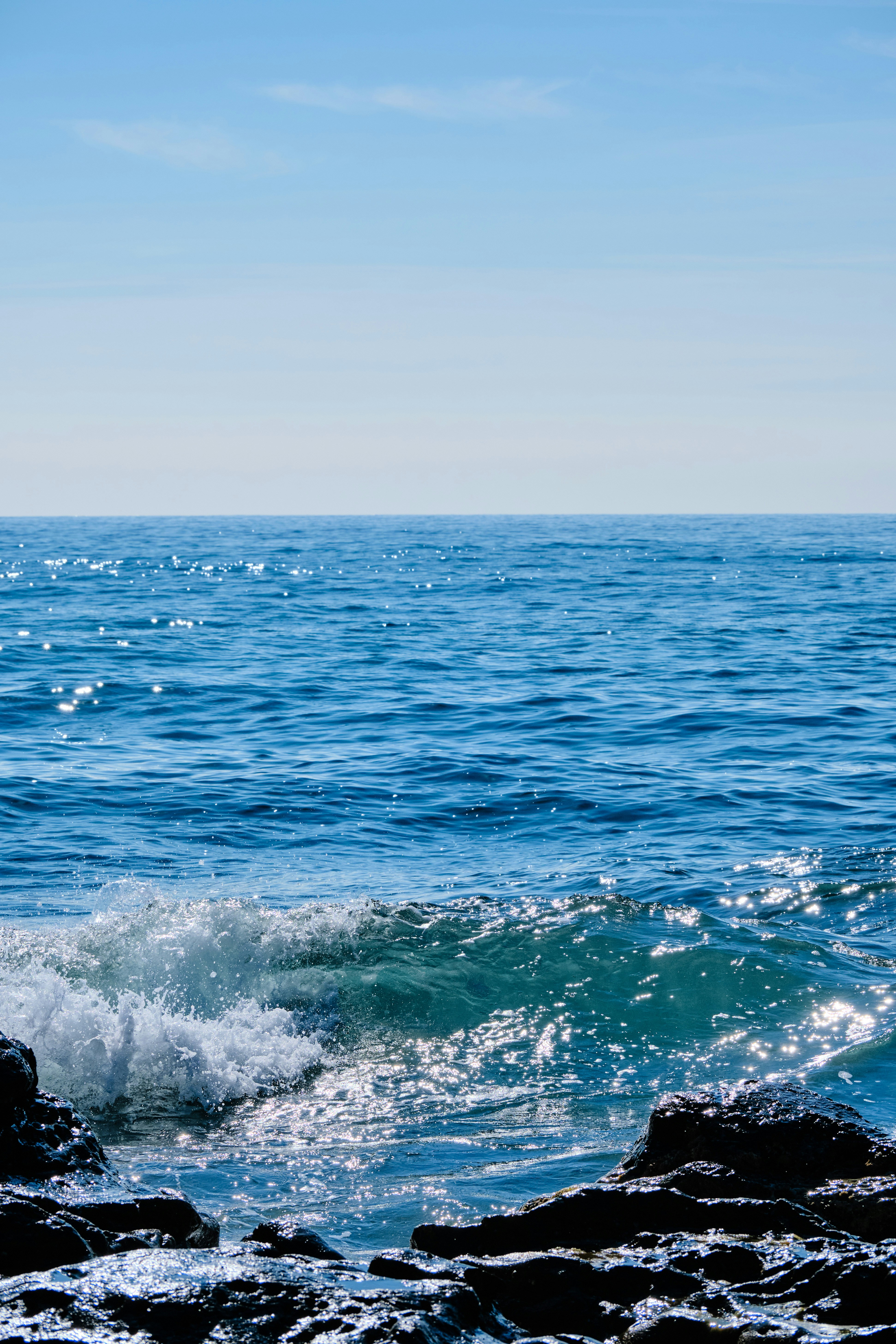 Coastline Crest: Sunlit Ocean Between Sky and Rocks