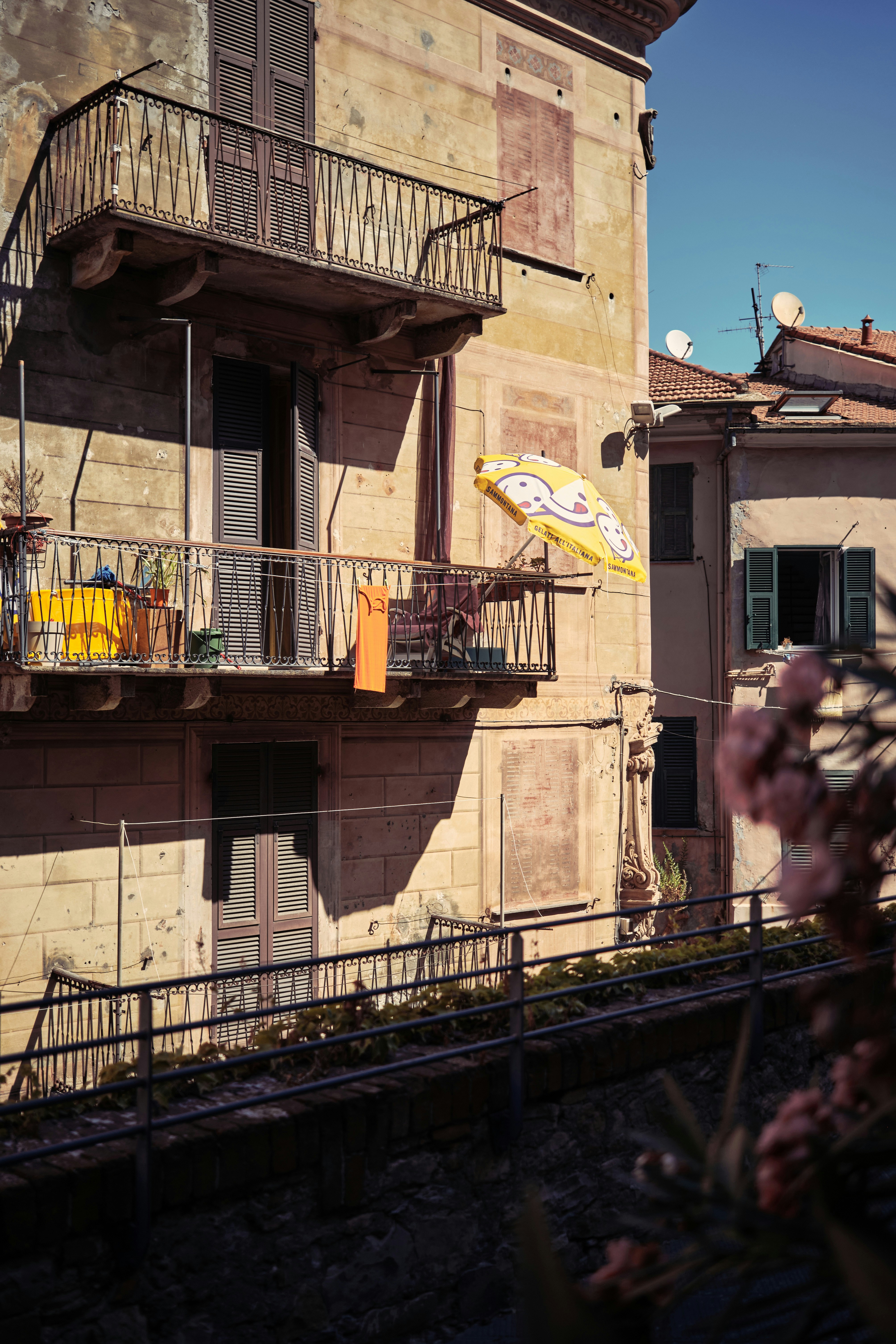 Sunlit Balcony with Laundry and Umbrella in a Mediterranean Street