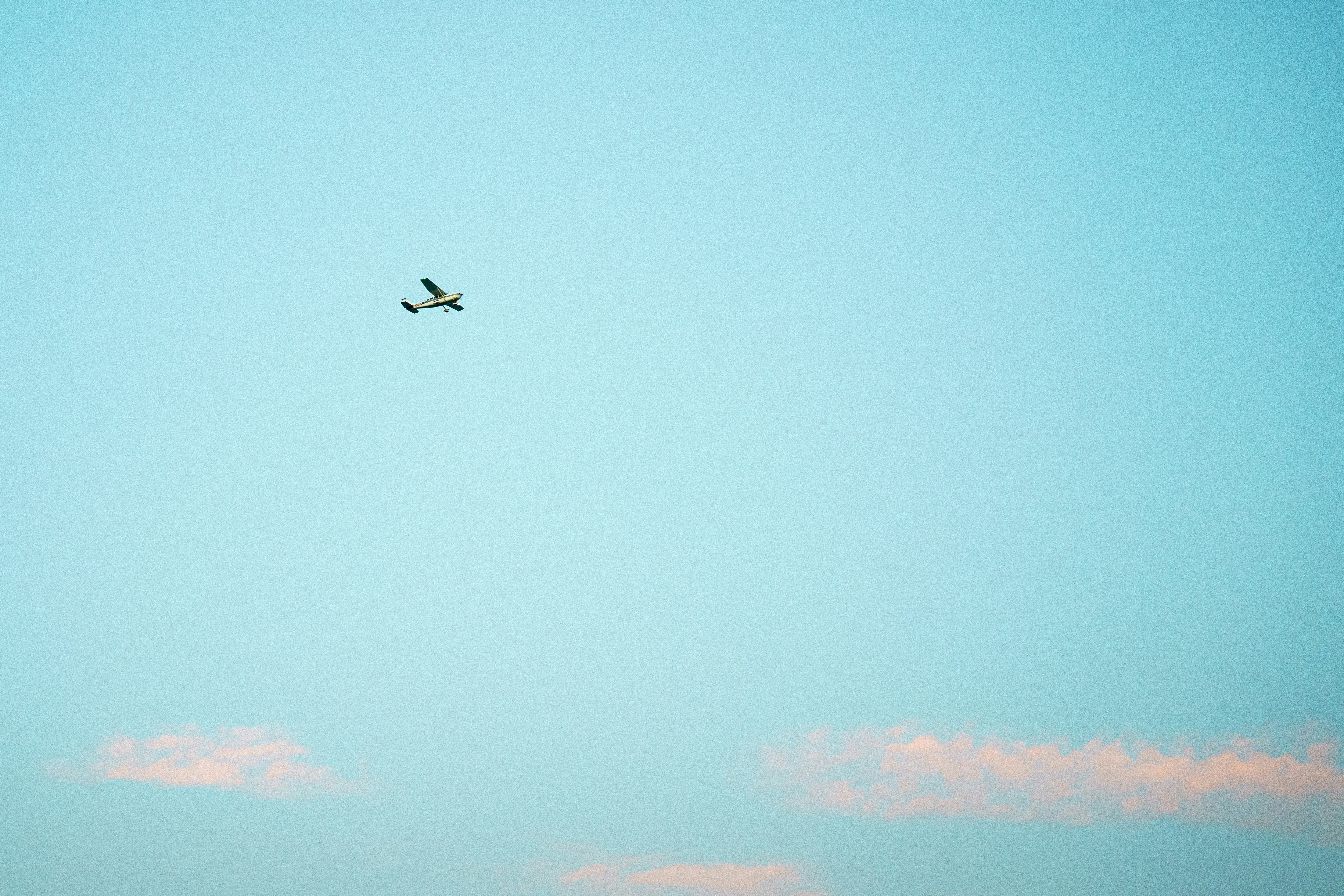 Tiny Jet, Vast Sky: A Lone Plane in a Pale Blue Expanse
