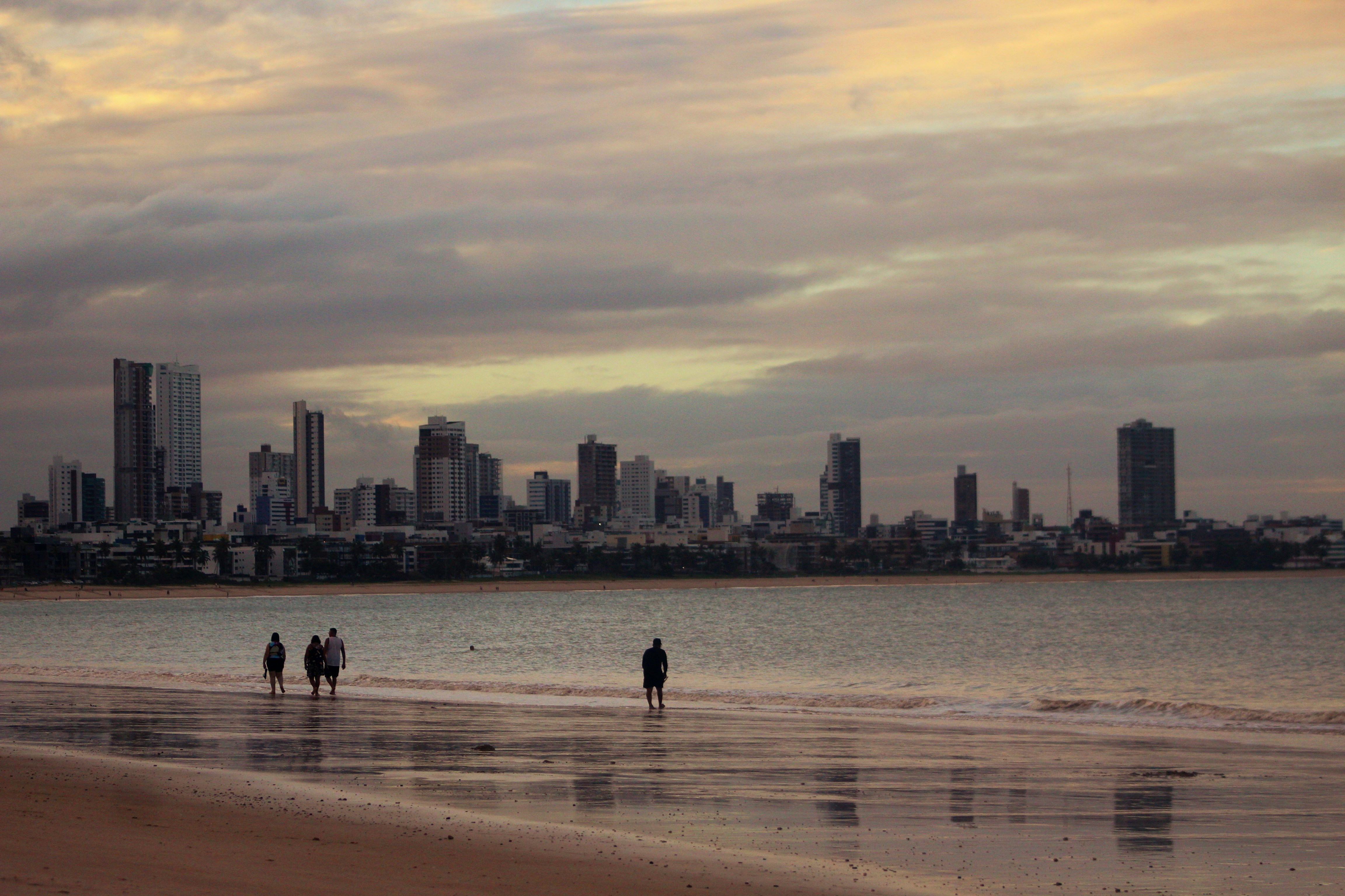 City shoreline at dusk: silhouettes and mirrored water on a quiet beach