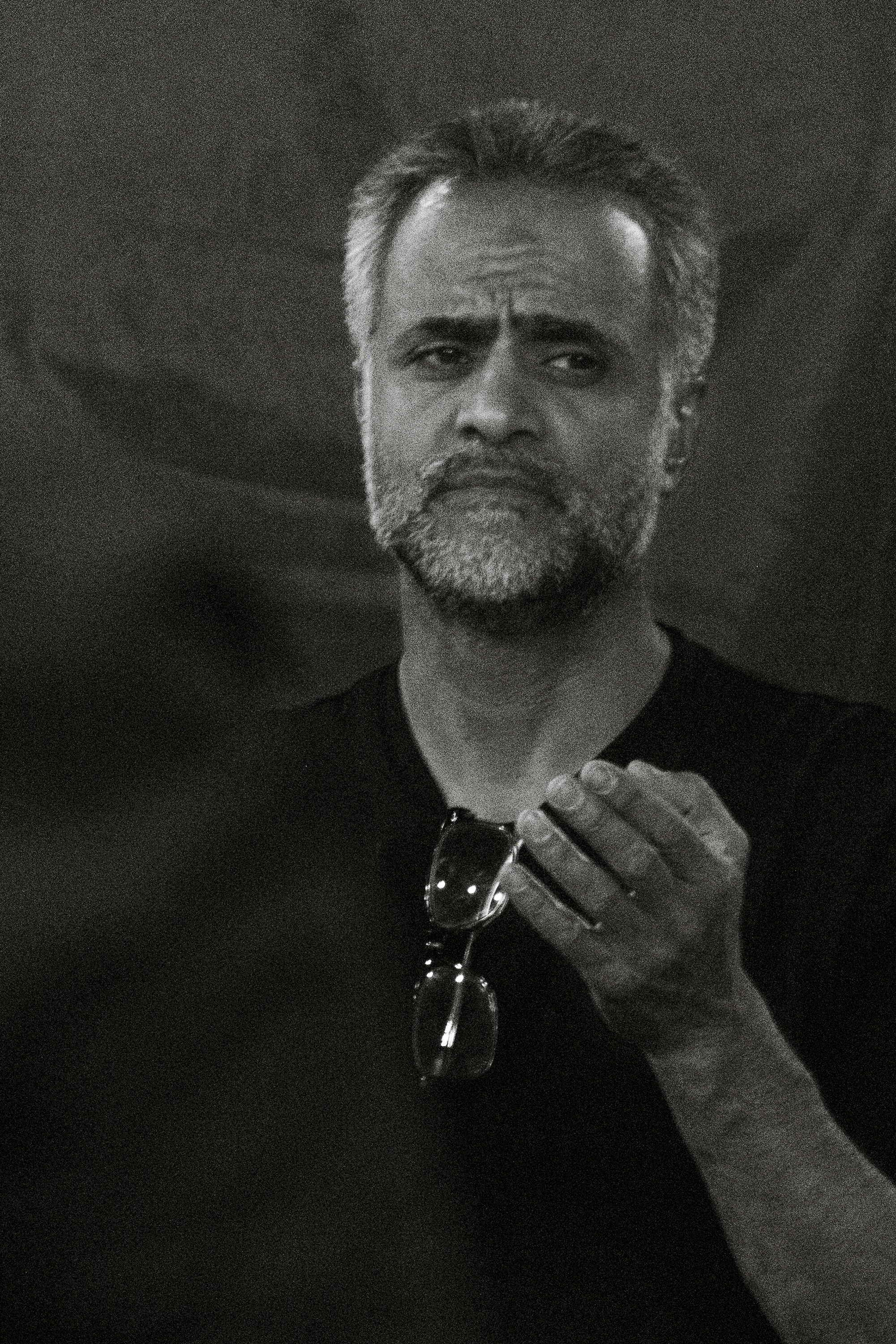 Quiet Authority: A Moment of Contemplation with Sunglasses in Hand