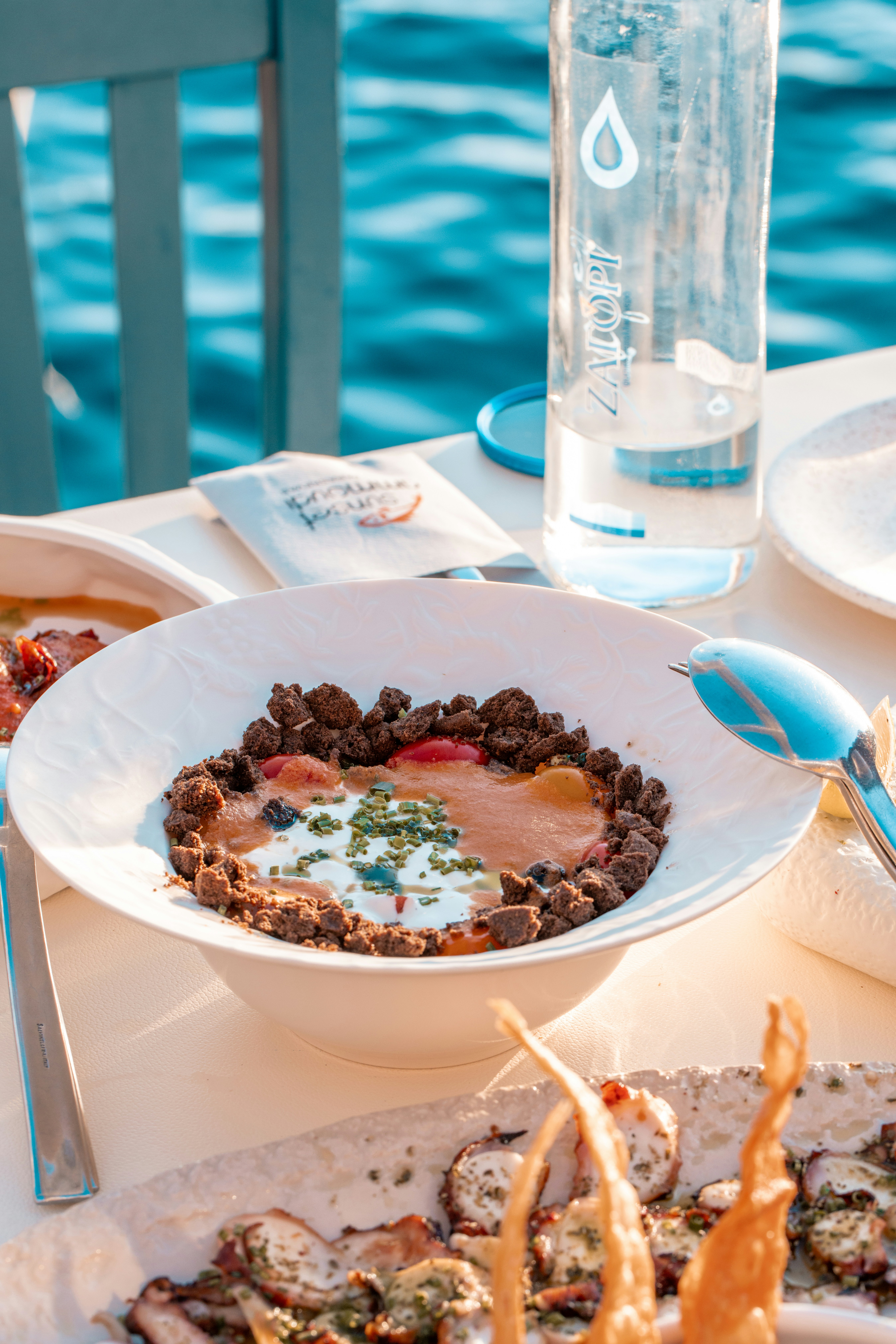 Creamy bowl of dessert soup with chocolate crumble on a sunlit seaside table