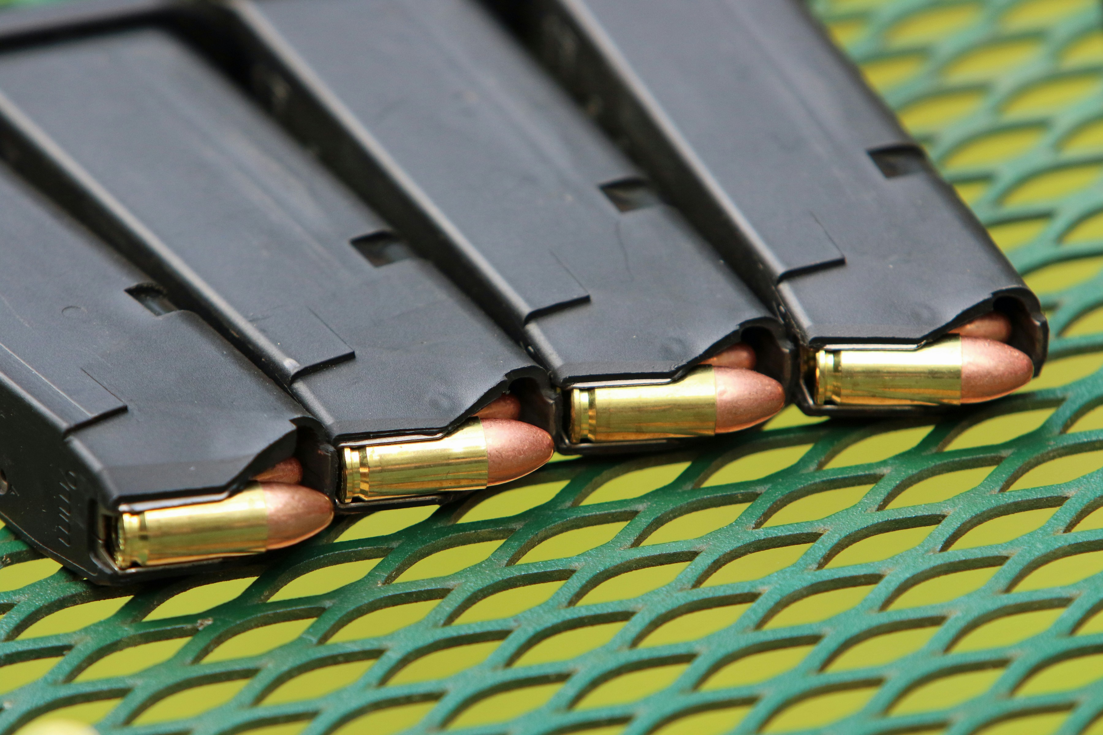 Rifle magazines lined up on a textured green surface