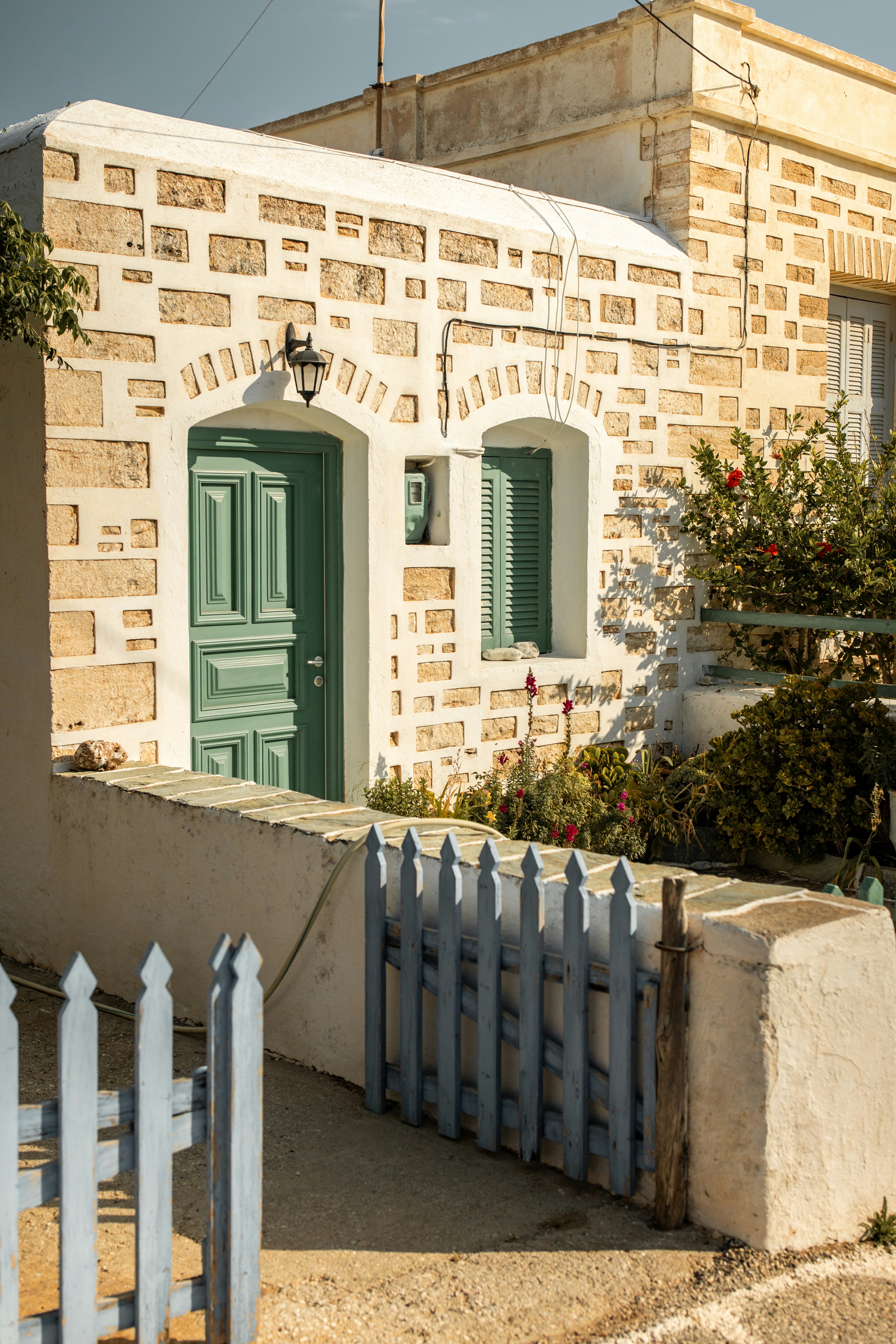 Sunlit Facade with Teal Door and Wisteria Shadow
