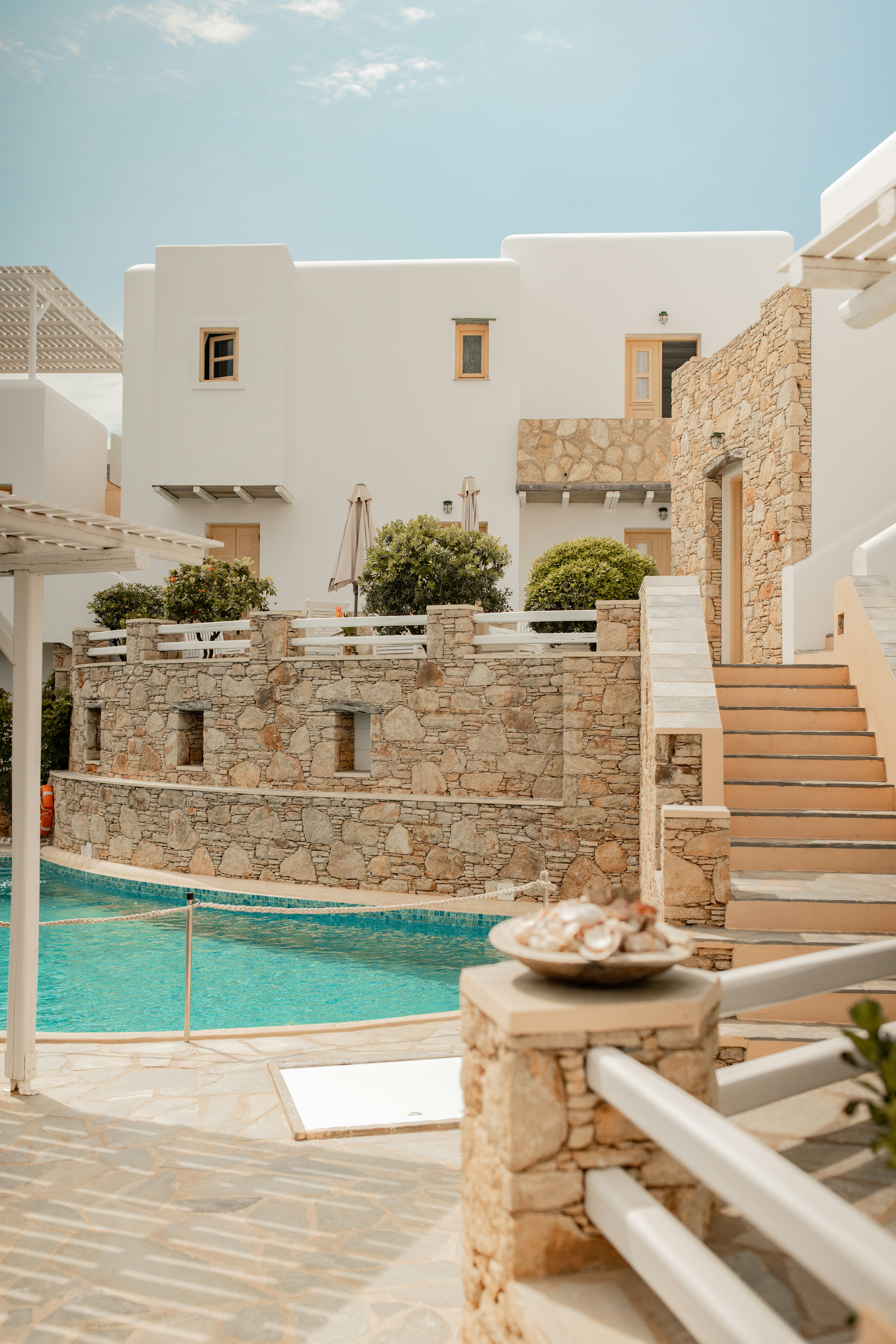 Terraced Oasis: Sunlit White Walls and Stone Balcony by the Pool