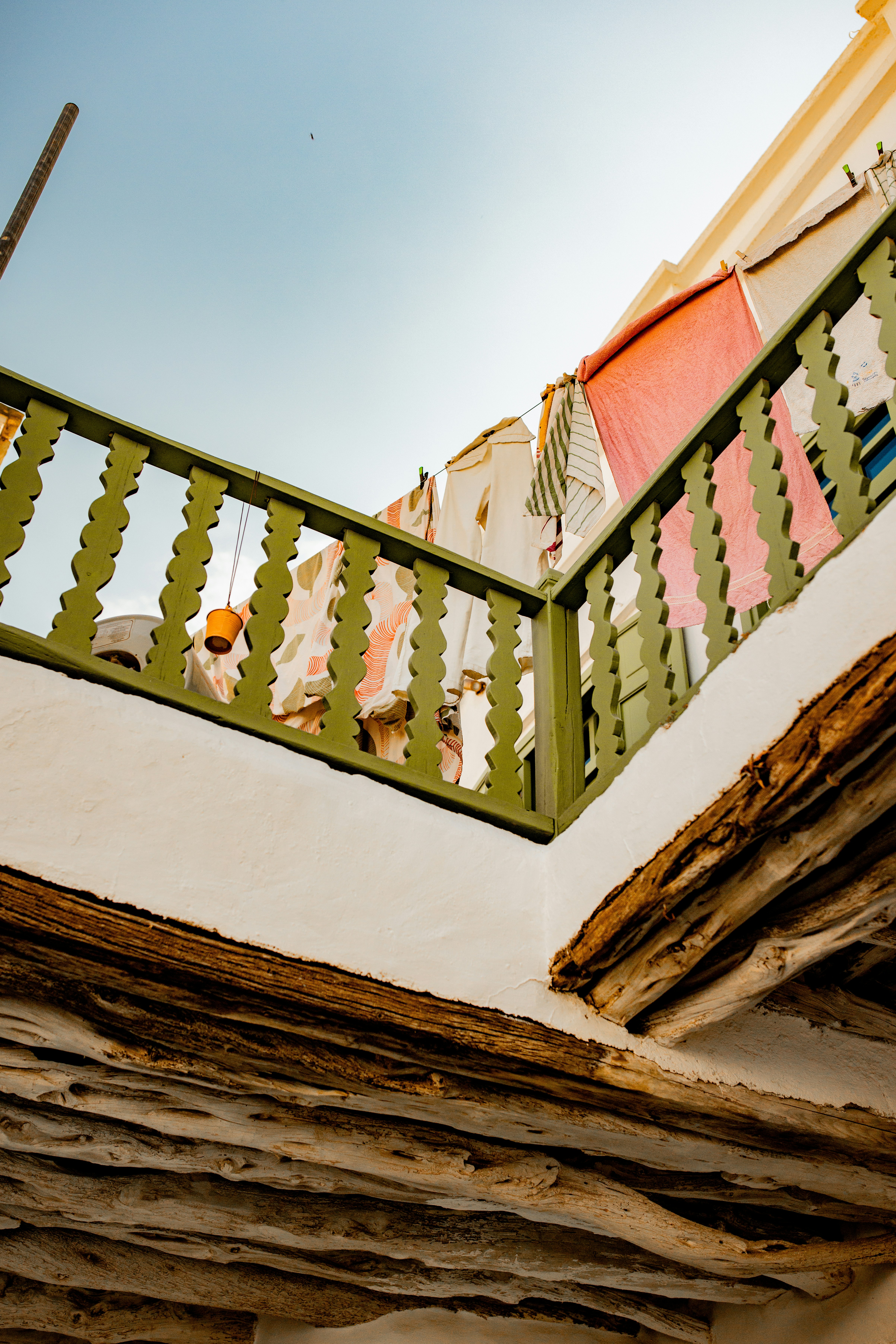 Sunlit Balcony Overlook: Green Railings and Weathered Beams