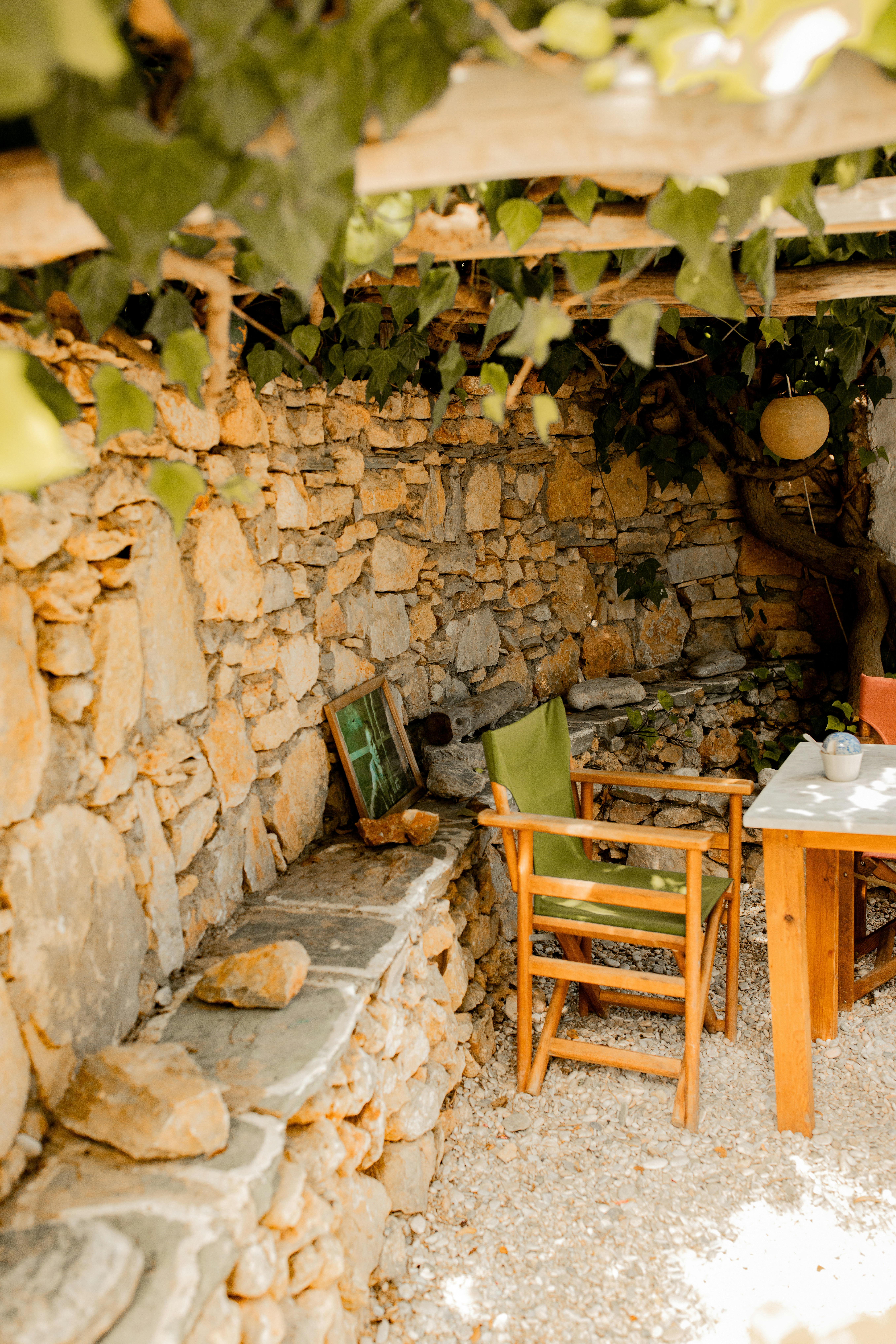 Stone-walled patio with wooden seating under leafy canopy