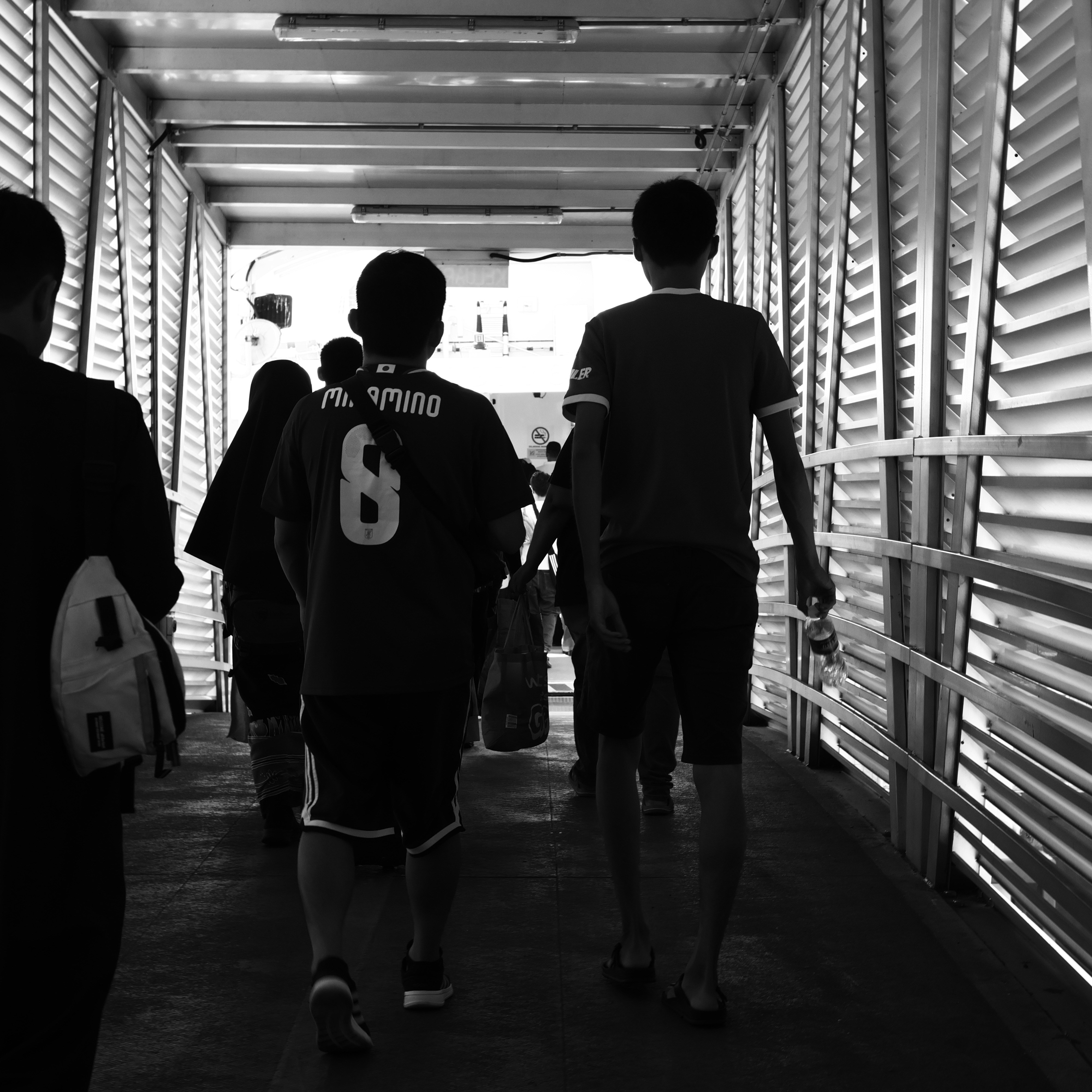 People Crossing a Sunlit Tunnel: A Black-and-White Walk Through the Passage