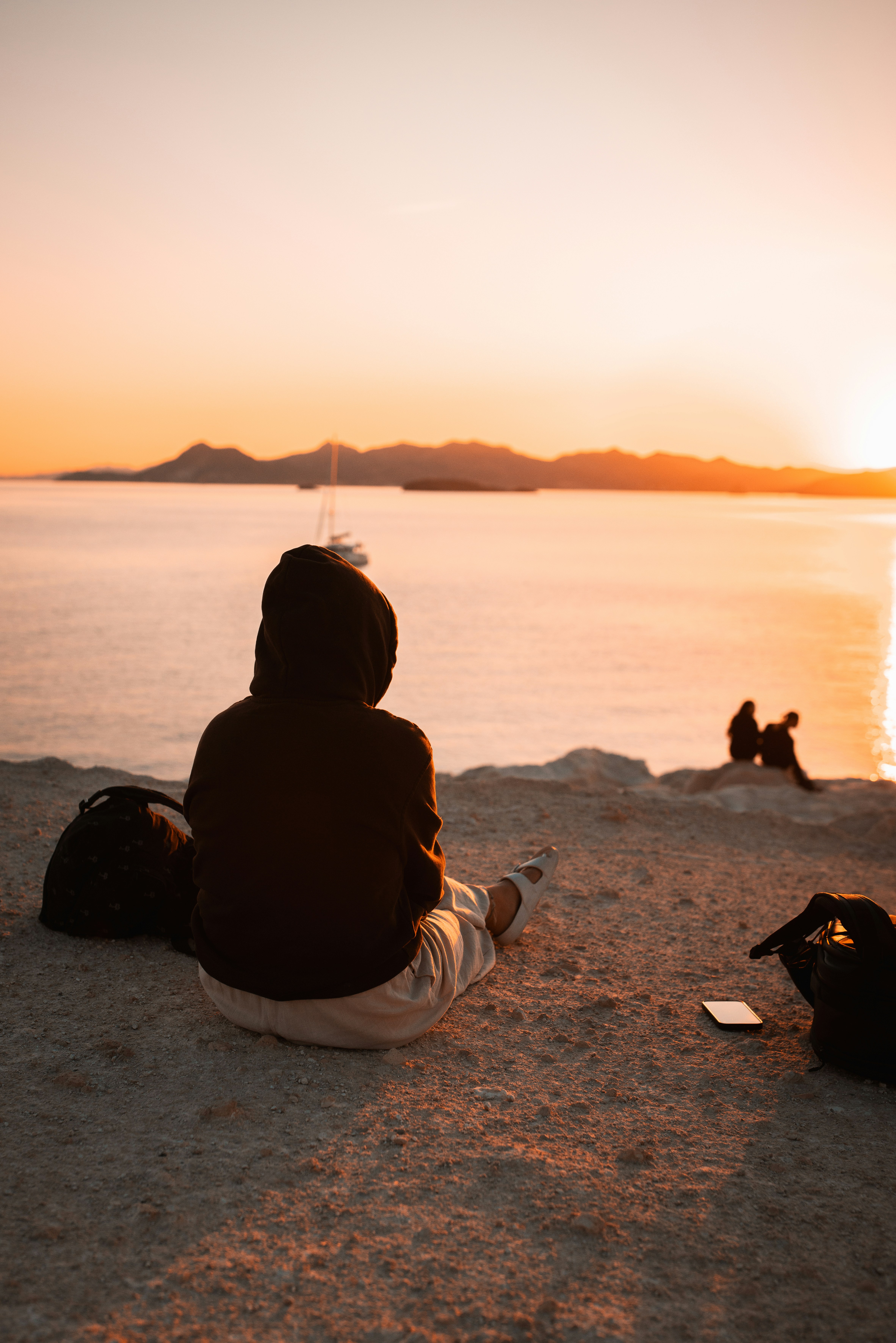 Sunlit Solitude: A Hooded Figure Overlooking a Quiet Sea