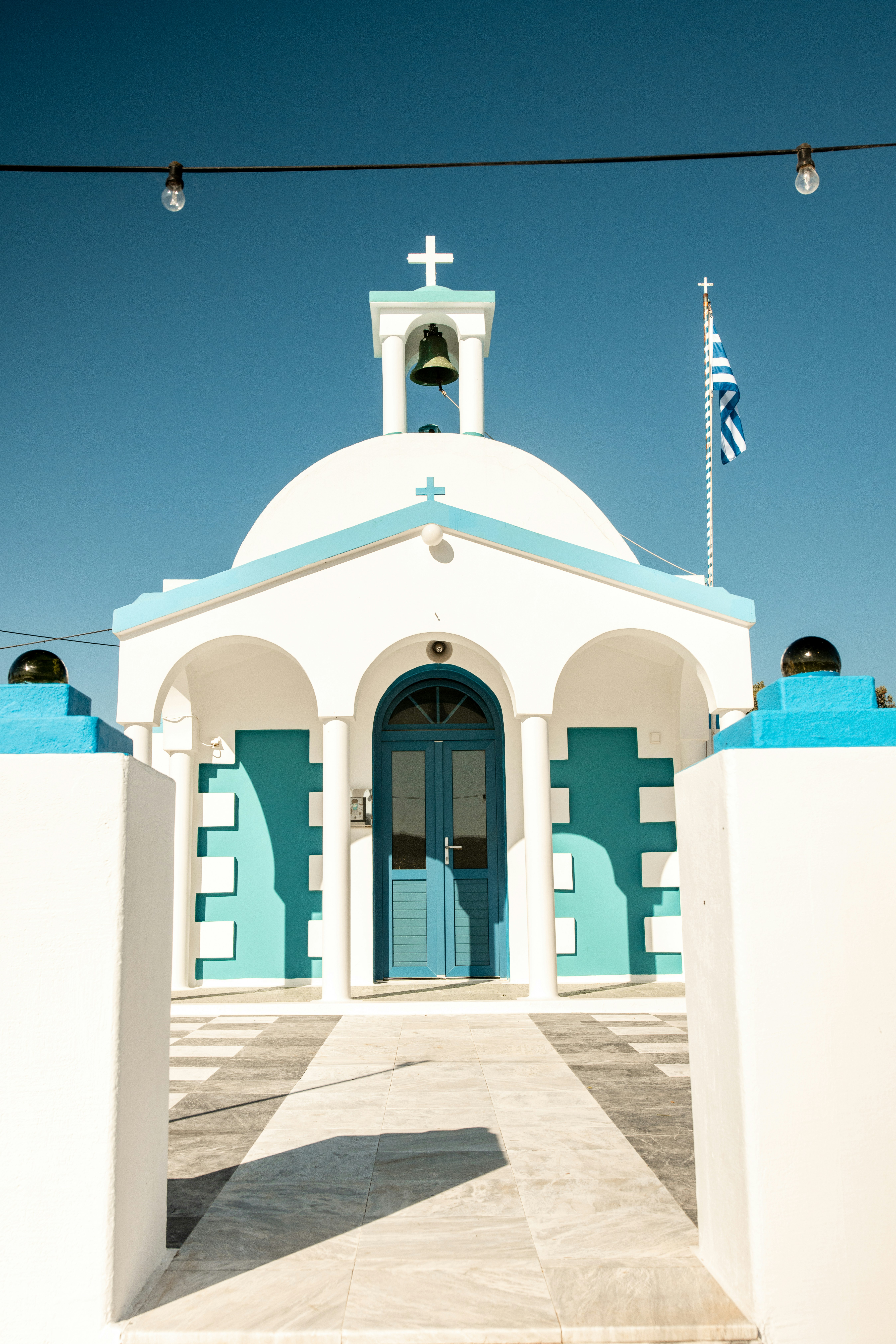 Blue and White Cycladic Chapel Framed by Pillar Valleys
