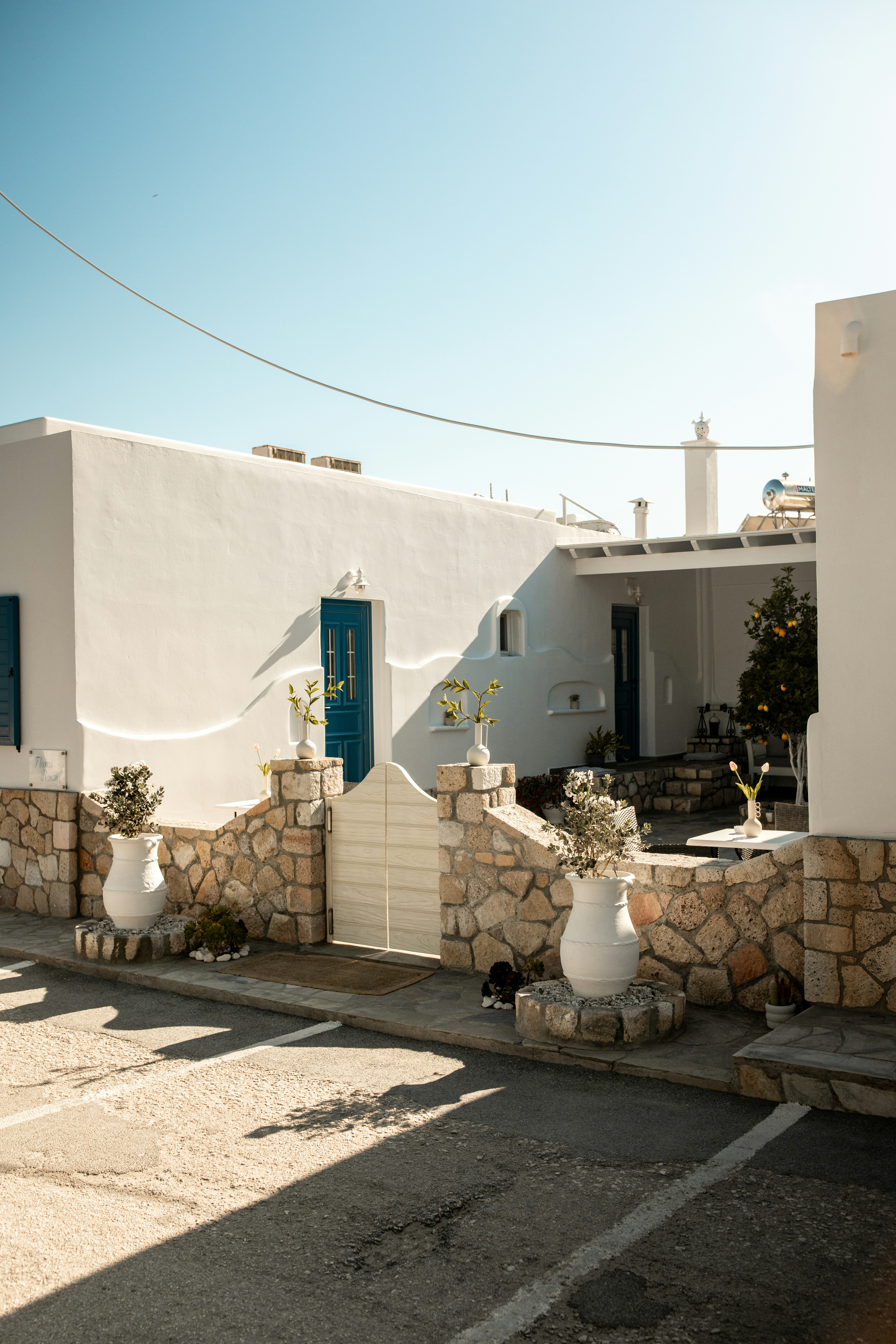 Whitewashed Courtyard with Blue Doorway and Stone Planters