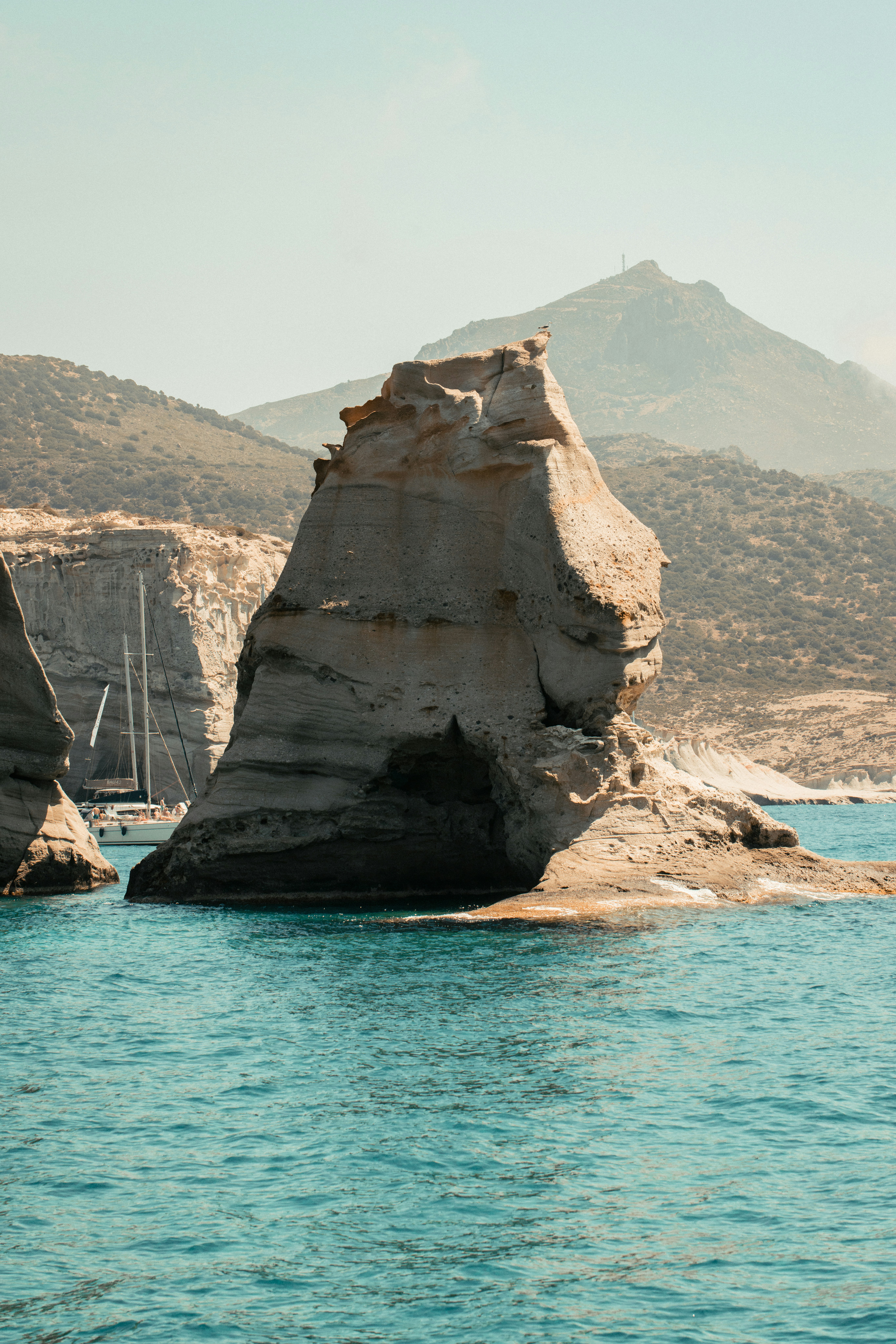 Stone Sentinel Rising from Teal Waters under a Distant Peak