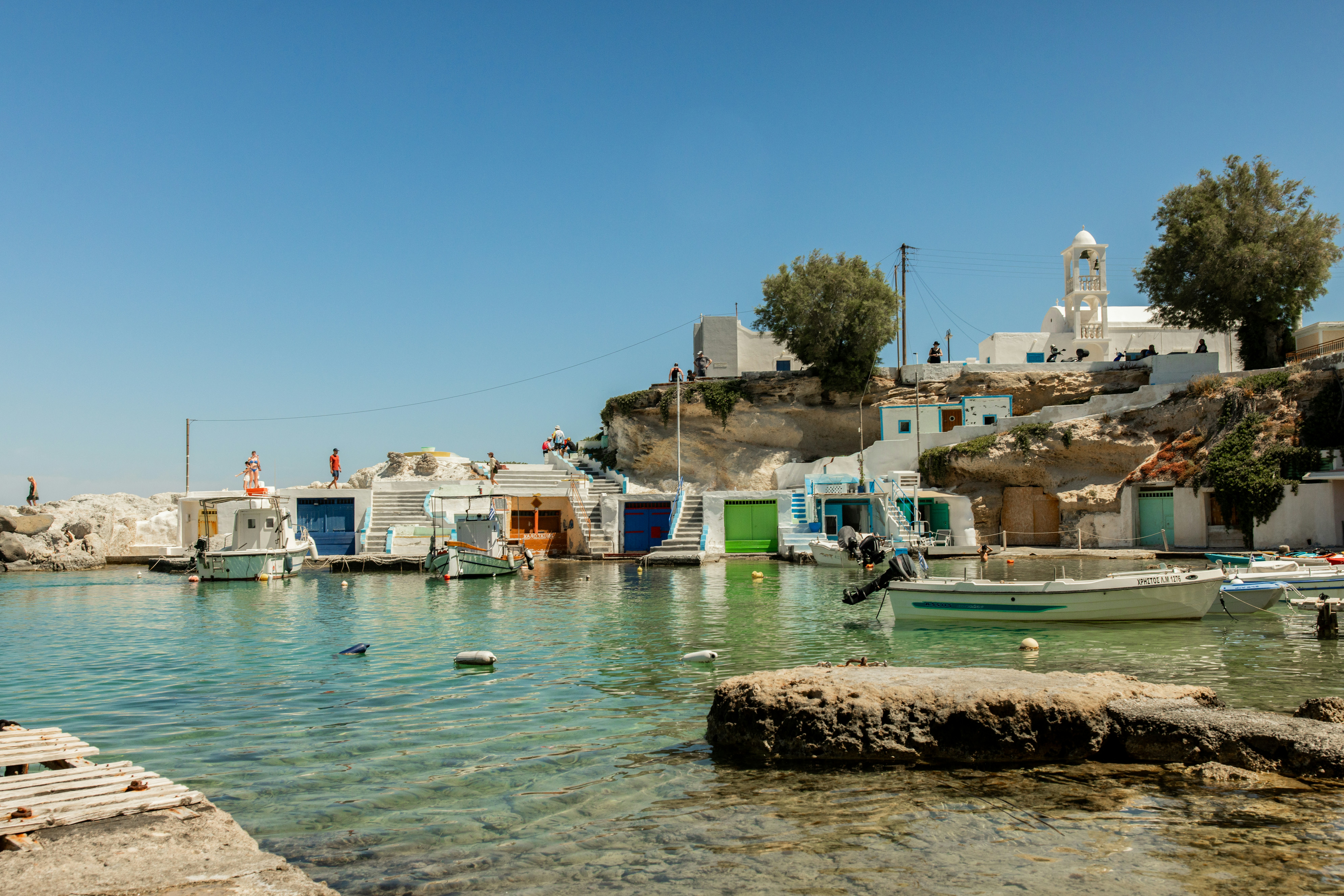 Colorful waterfront charm: boats, huts, and chapel above a tranquil cove