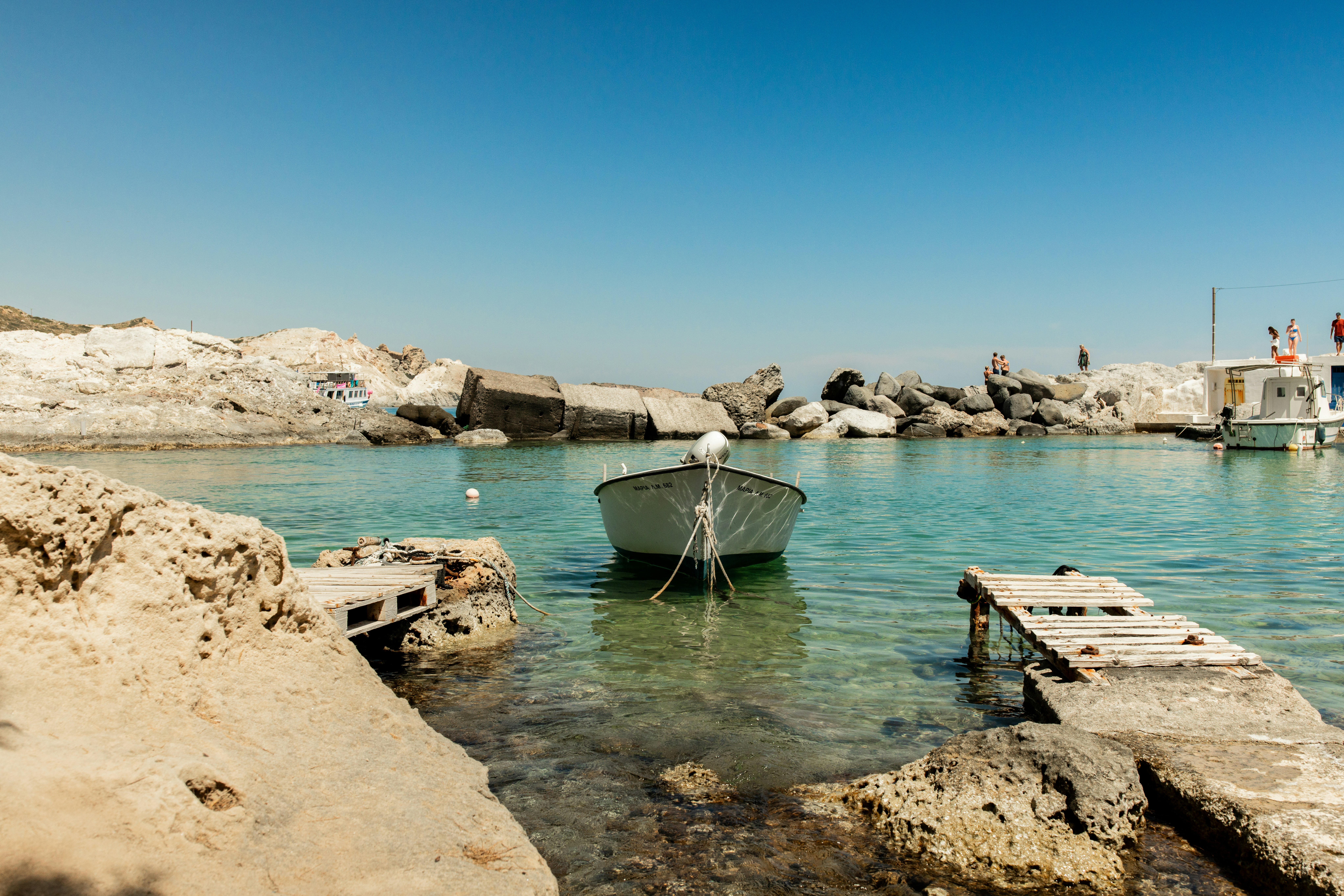 Quiet Boat in a Calm Harbor: Sunlit Stones and Clear Water