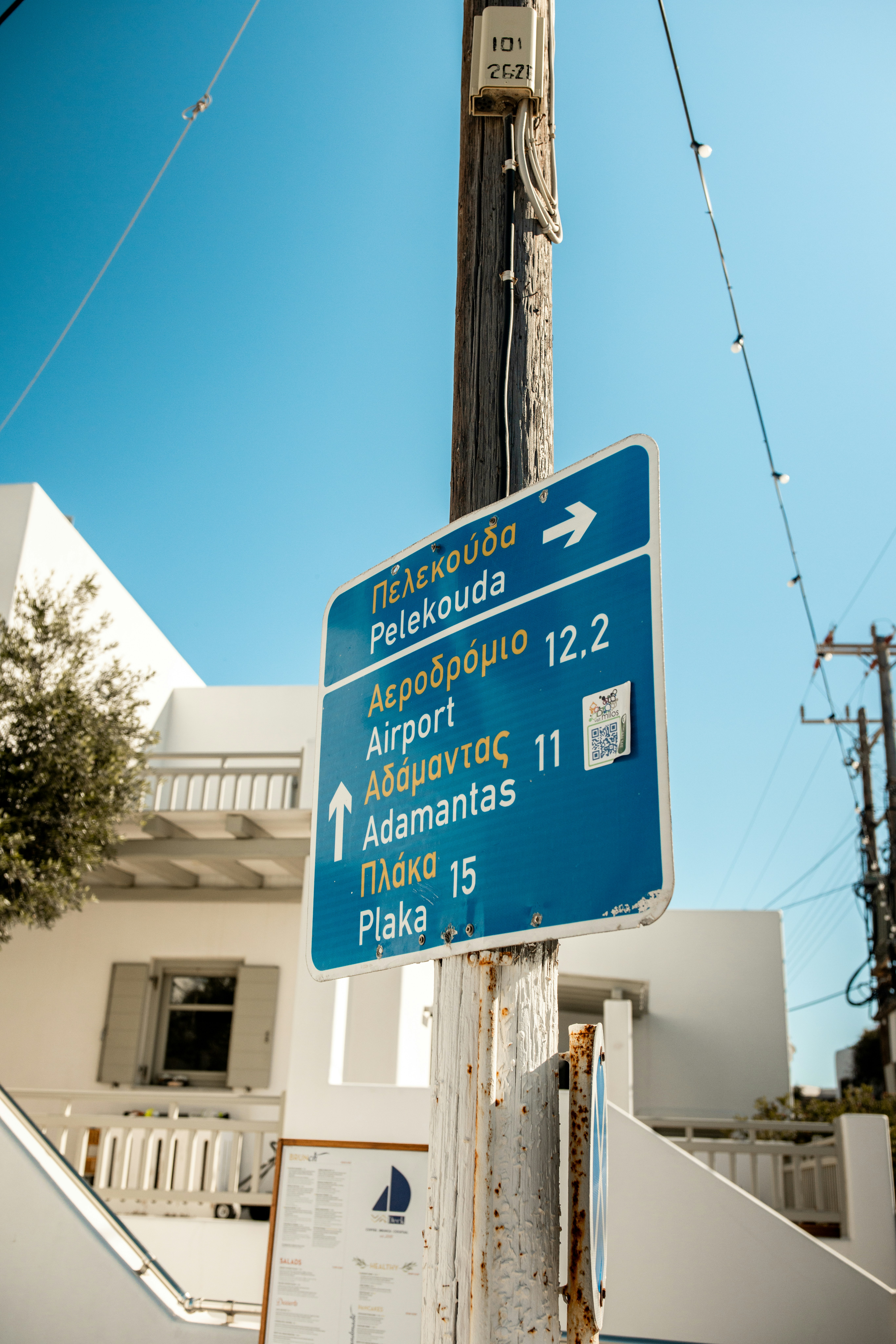 Blue Wayfinding Sign Amid Sunny Aegean Facade