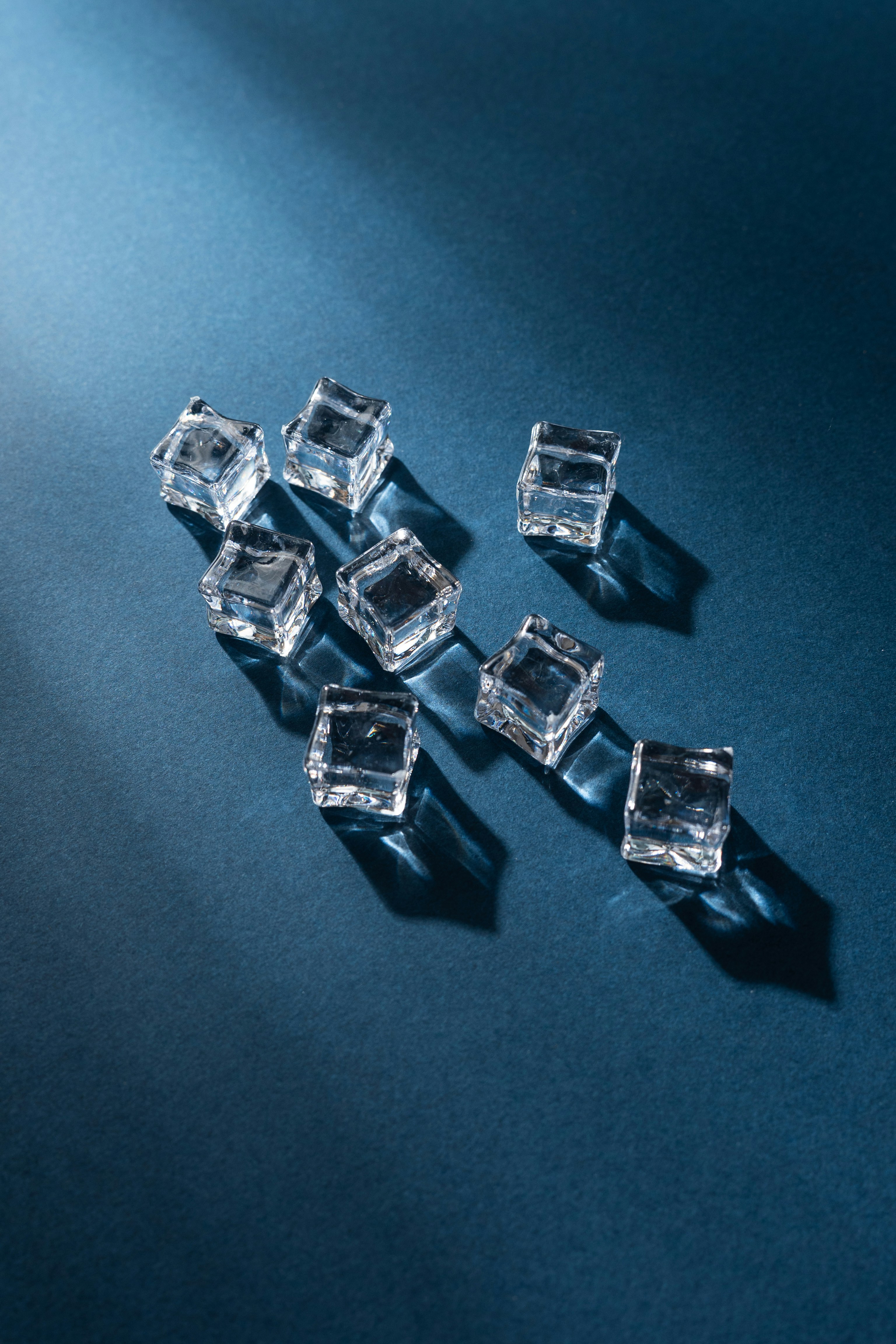 Ice Script: A Geometric Scatter of Glass Cubes on Blue Studio Light