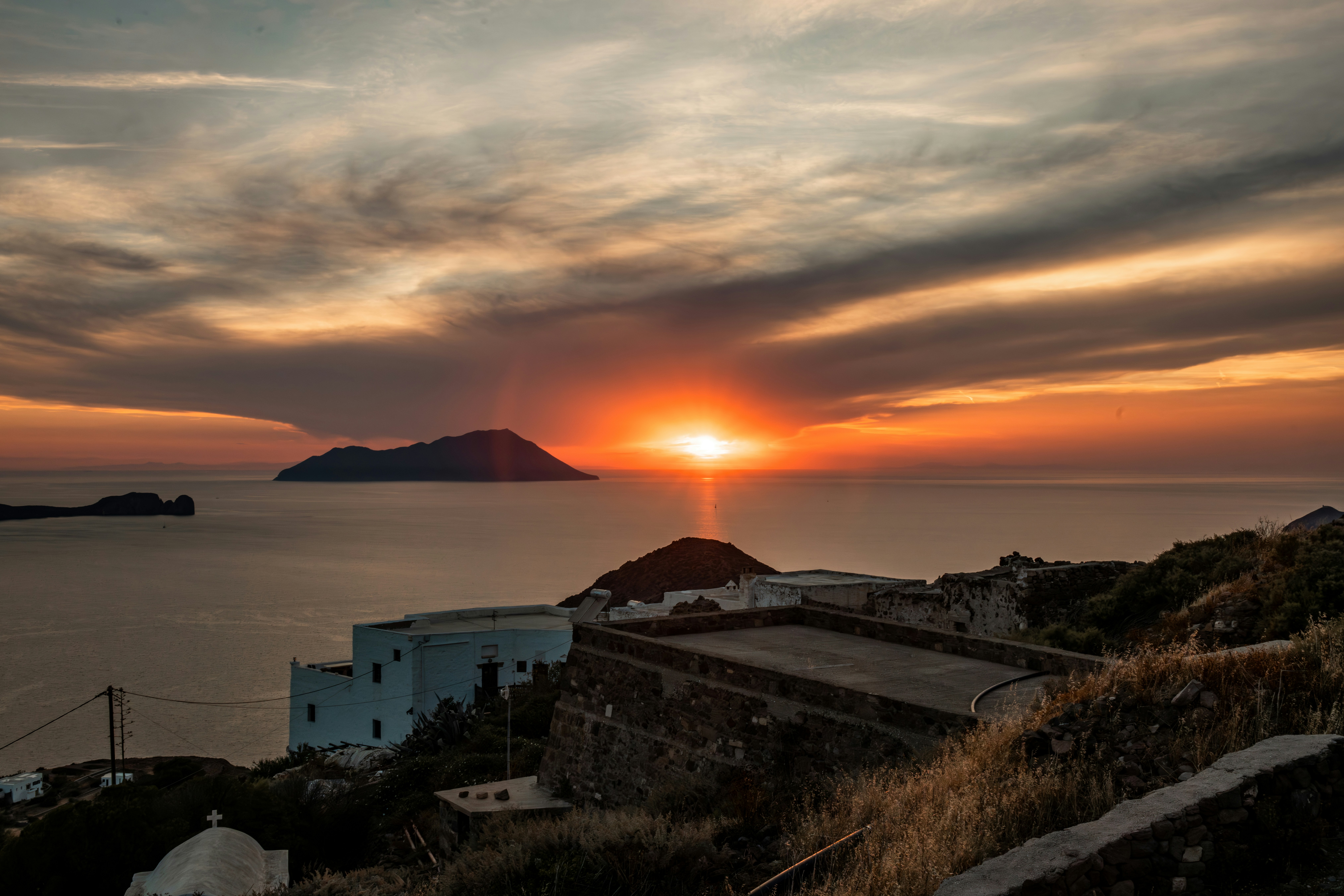 Sunset over a coastal village: basalt walls and whitewashed homes bathed in orange light
