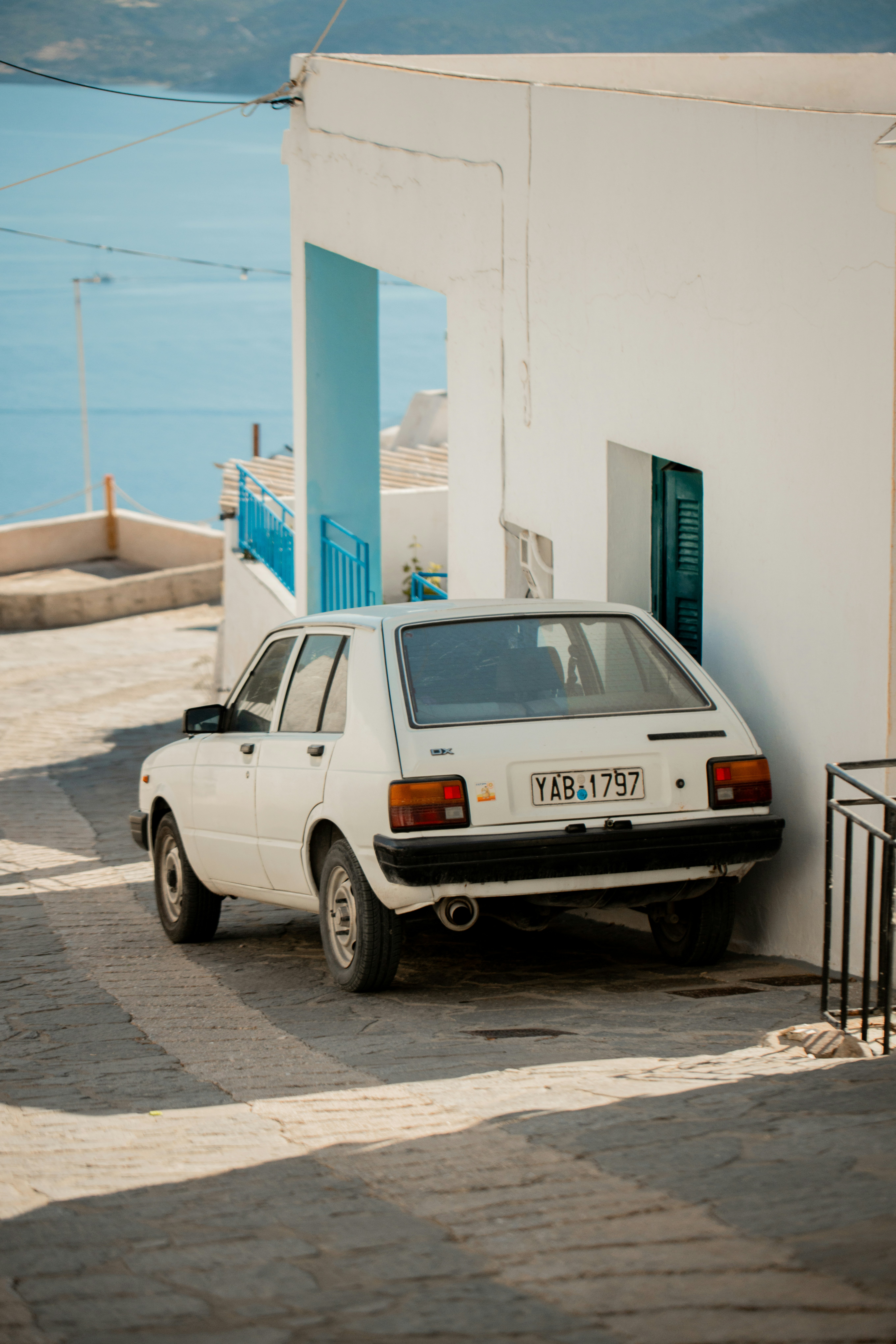 White hatchback tucked against a sunlit Mediterranean wall