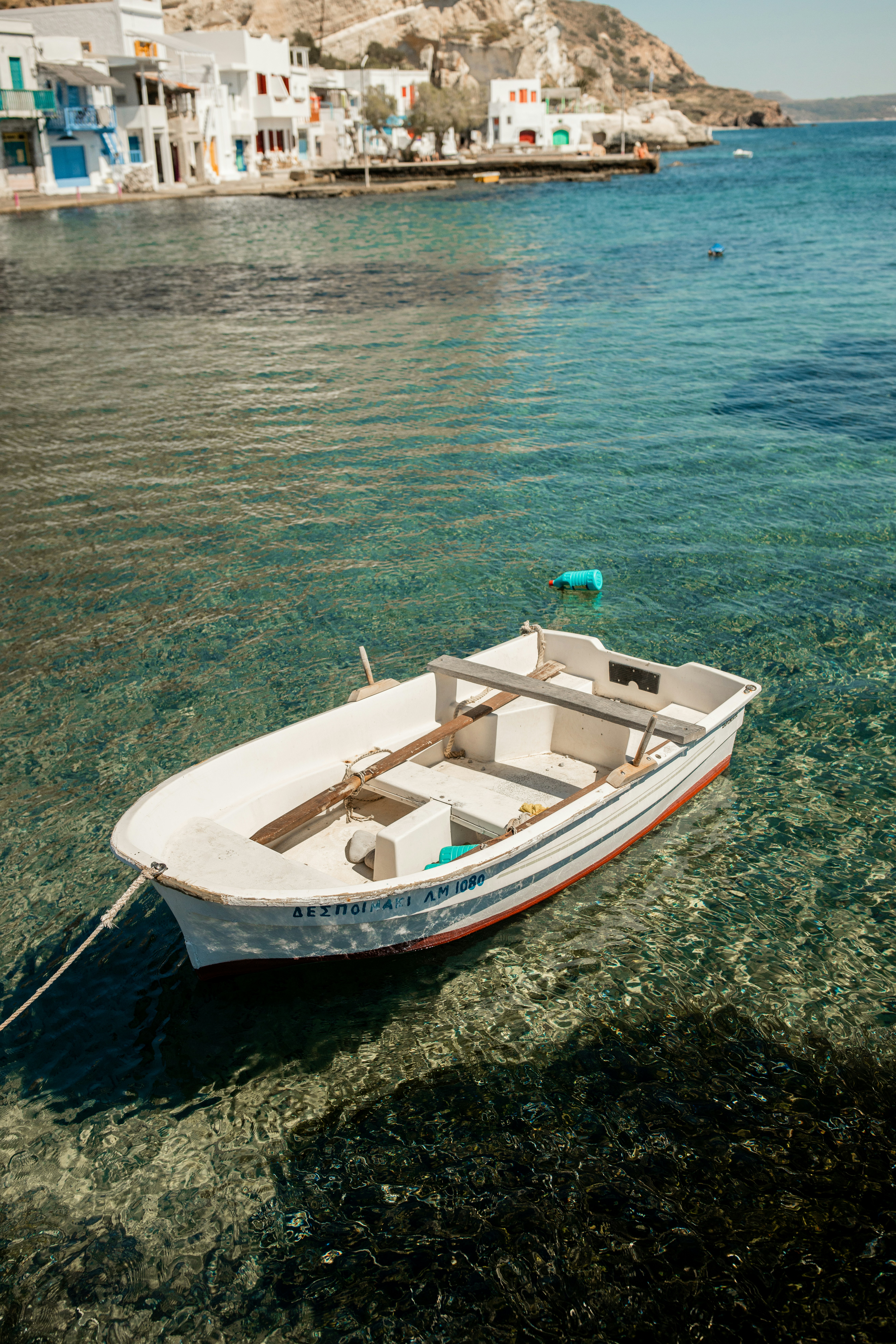 Boat at the turquoise cove: sunlit harbor of a Cycladic shore