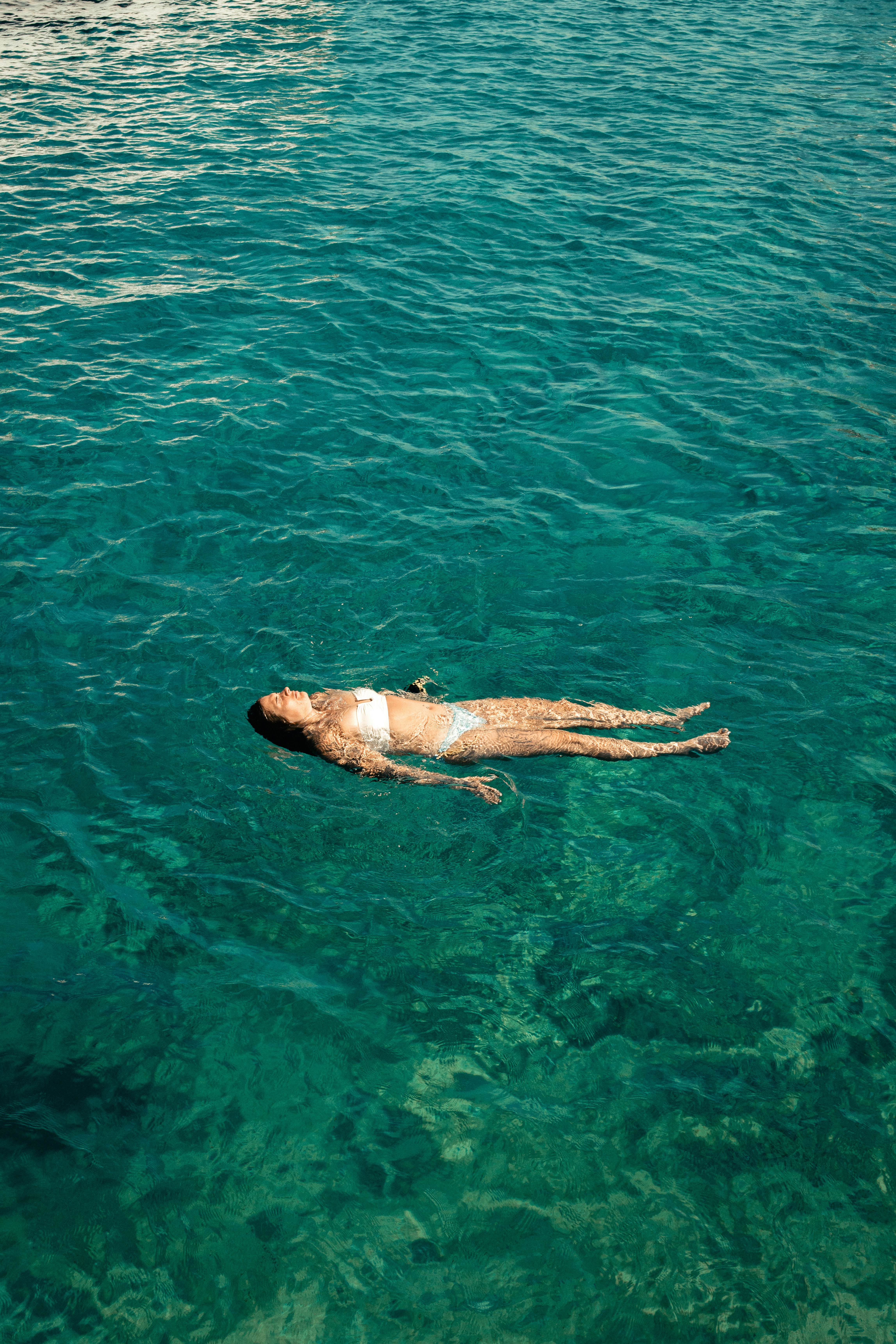 Floating Leisure: A sunlit figure drifts on turquoise calm