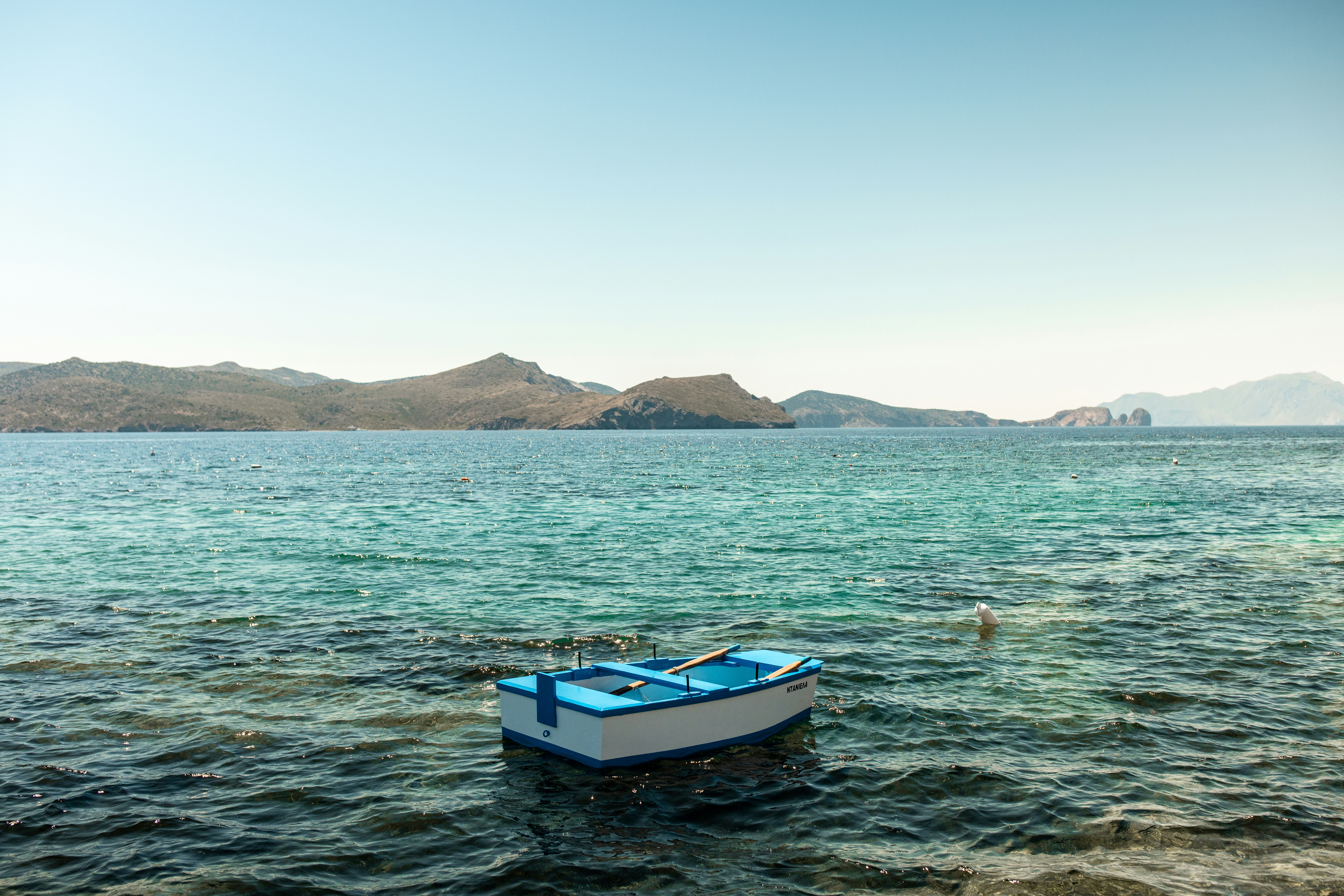 Blue Boat on Quiet Aquamarine Sea Under Clear Sky