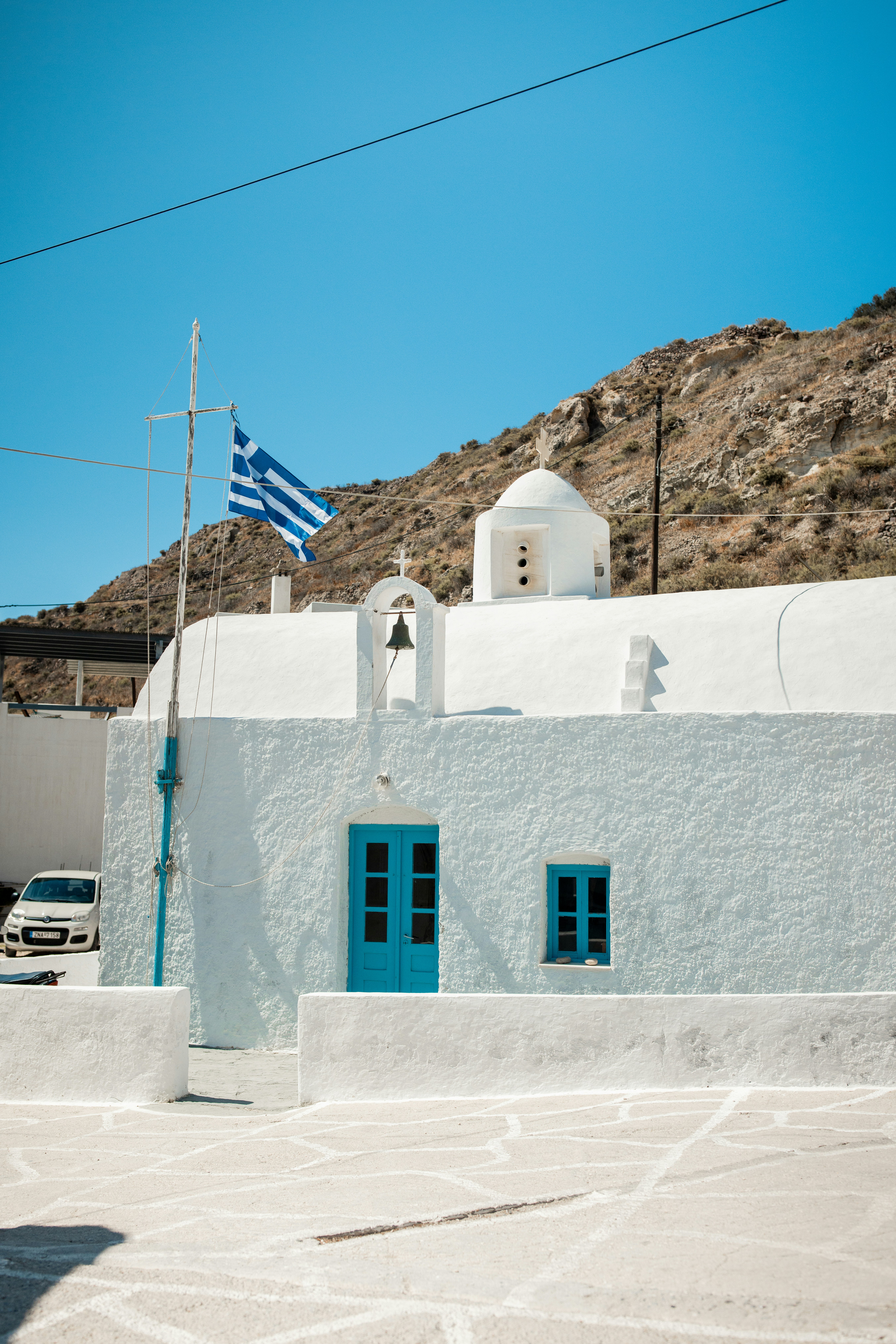 Whitewashed Greek Church with Blue Doors under a Clear Blue Sky