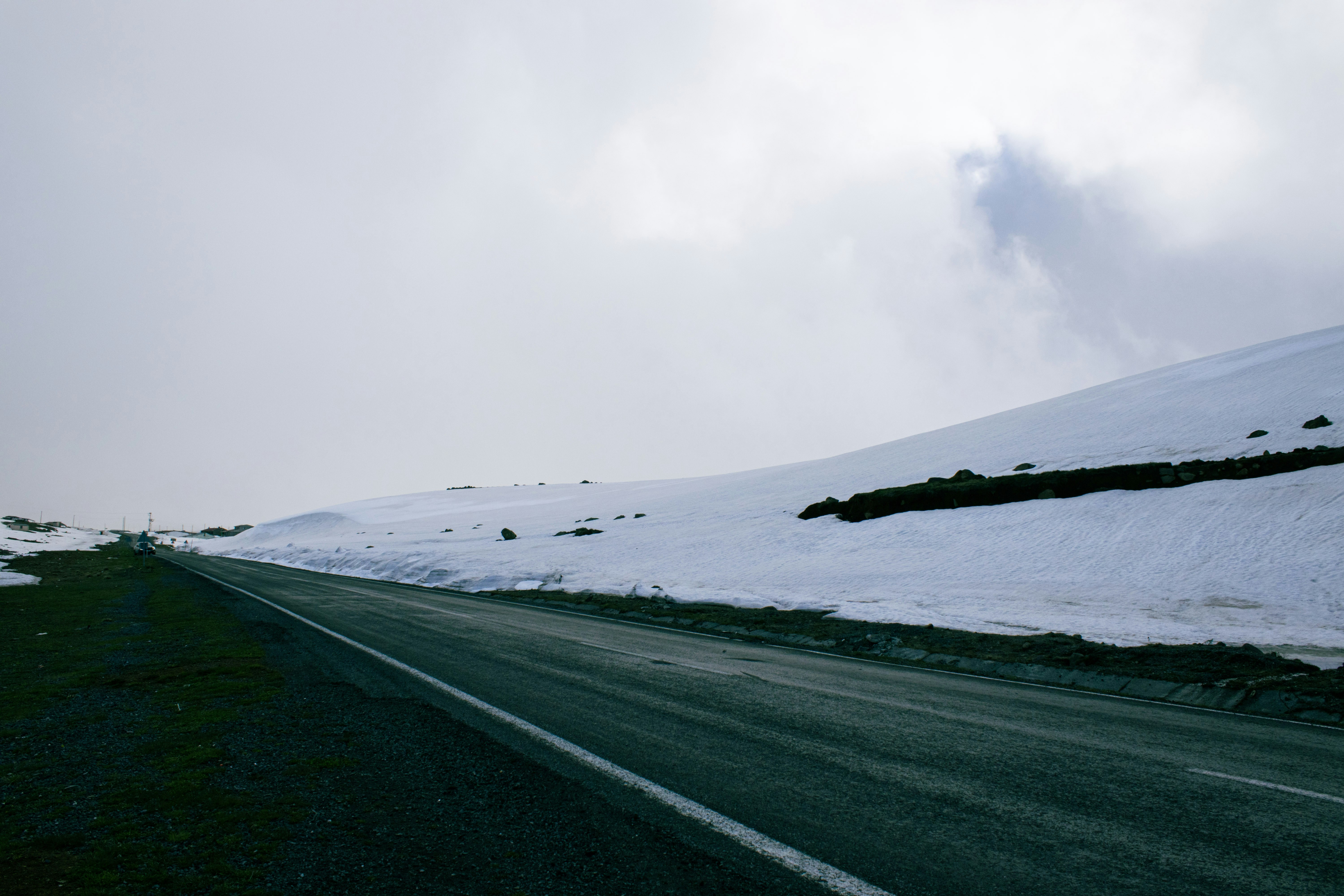 Desolate Asphalt Leading Toward Snow-Cedared Horizon