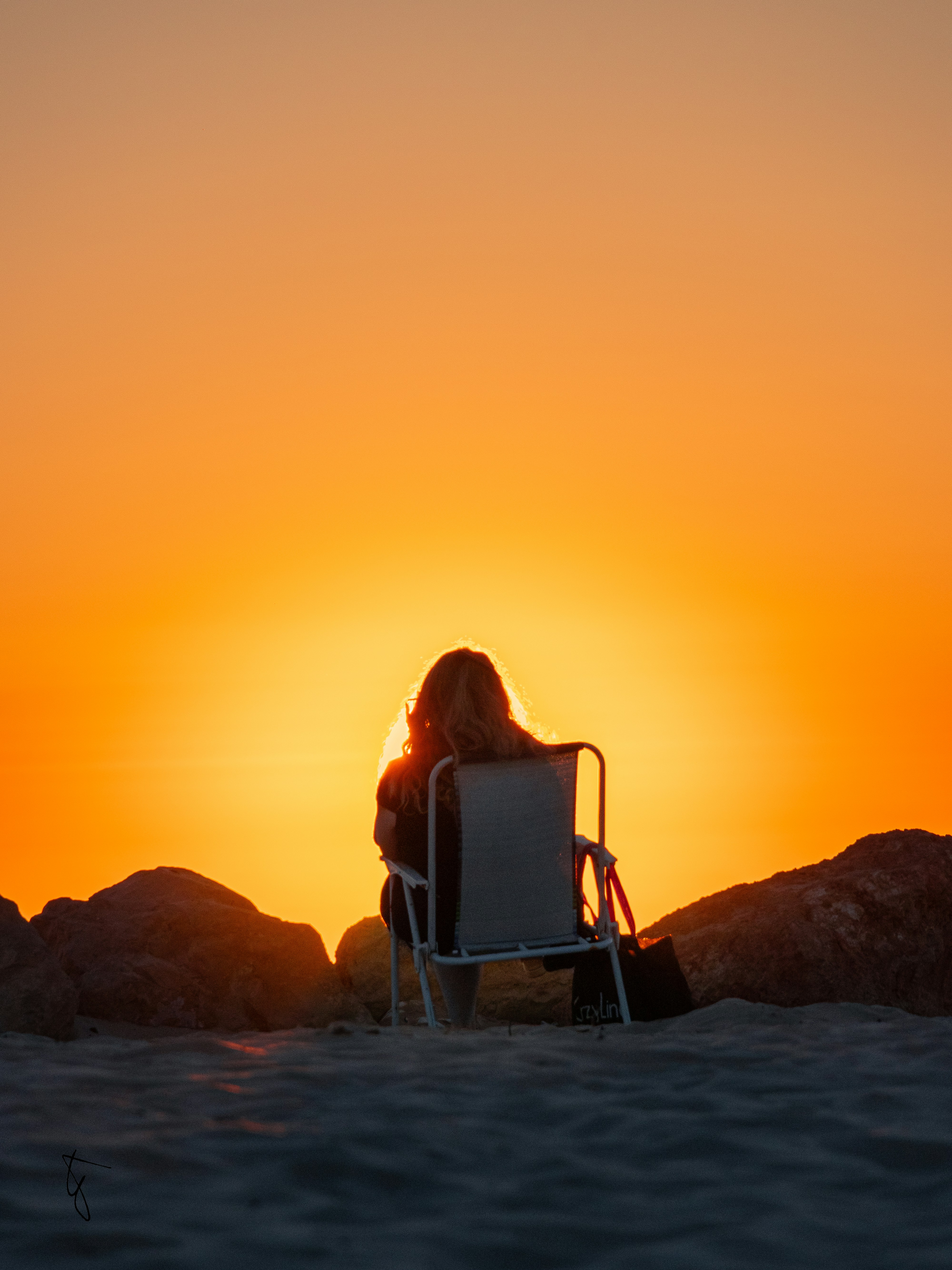 Sunset Solace: A Seated Silhouette Beneath a Flaming Horizon