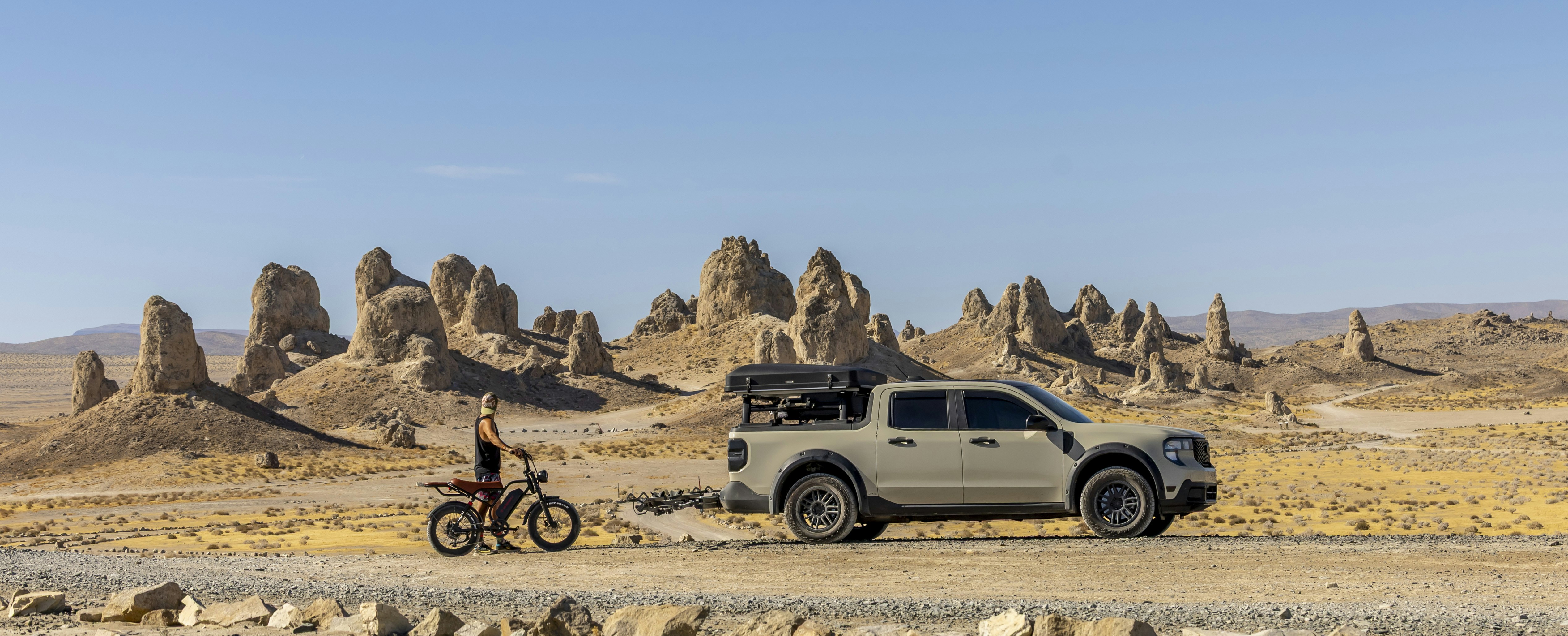 Desert Crossing: The SUV and Cyclist Converge Beneath Dragon-like Rock Spires