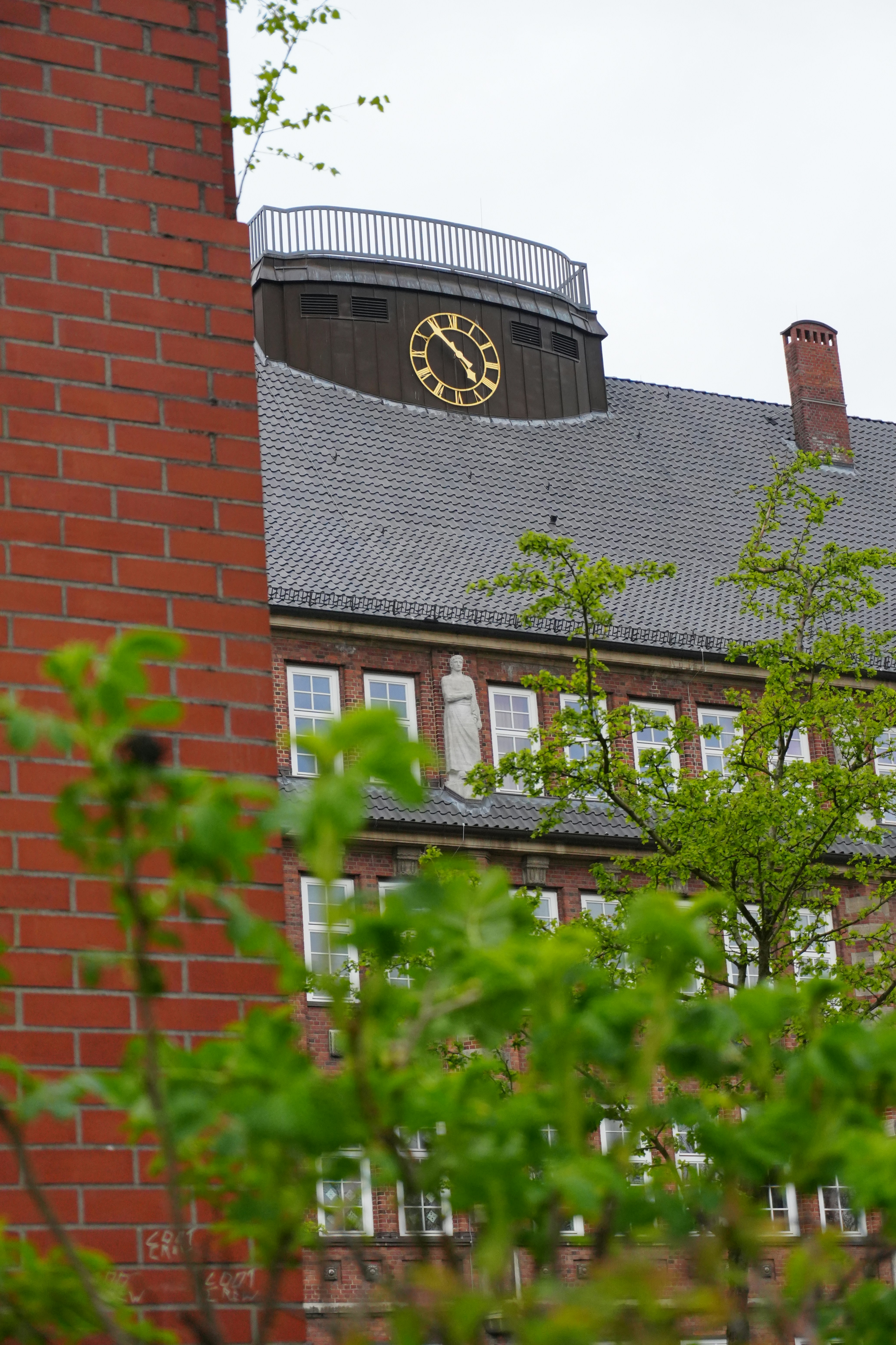 Clock Tower Above Brick Facade Framed by Spring Greenery