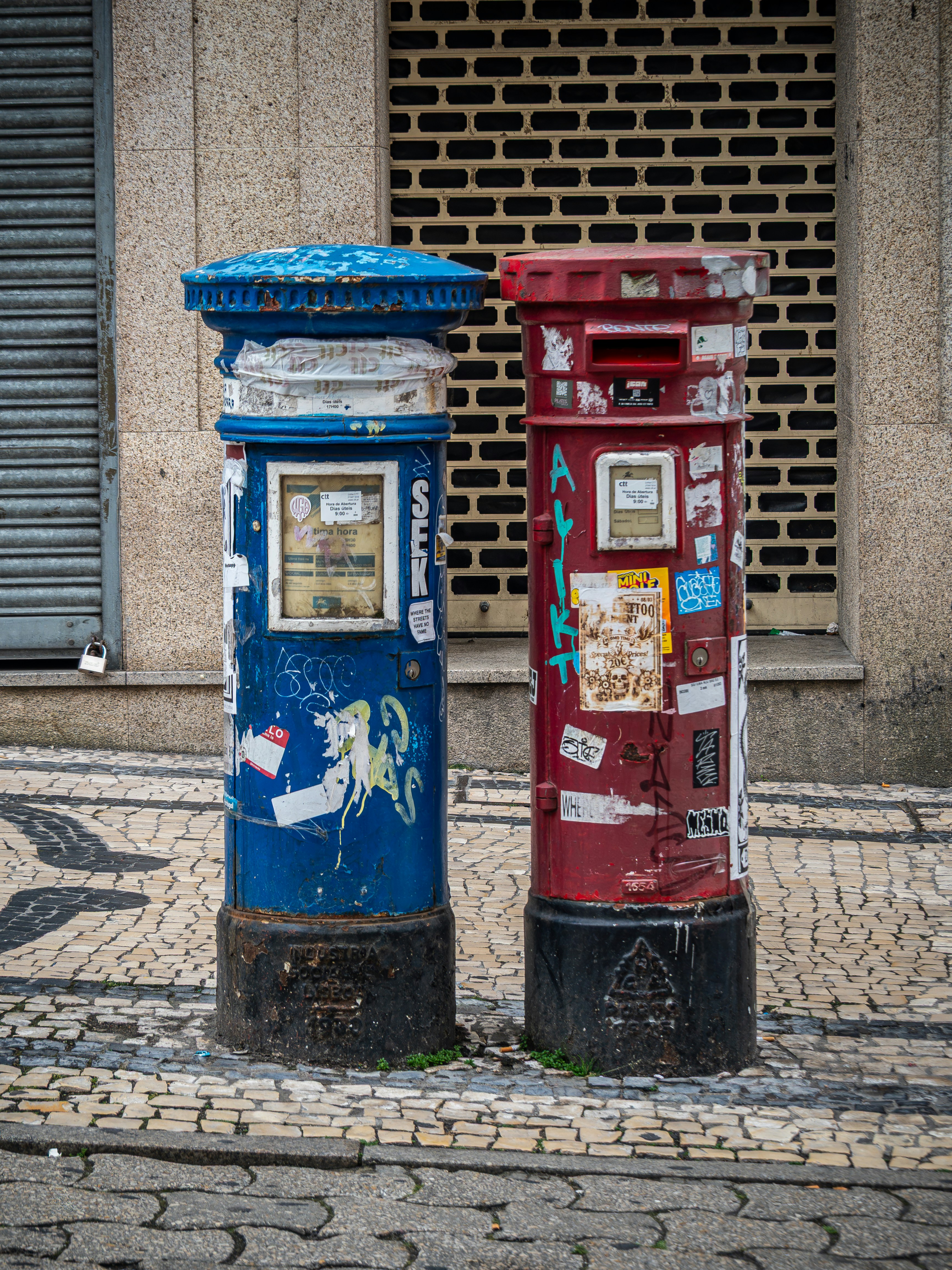 Two weathered mailboxes stand guard on a tiled sidewalk