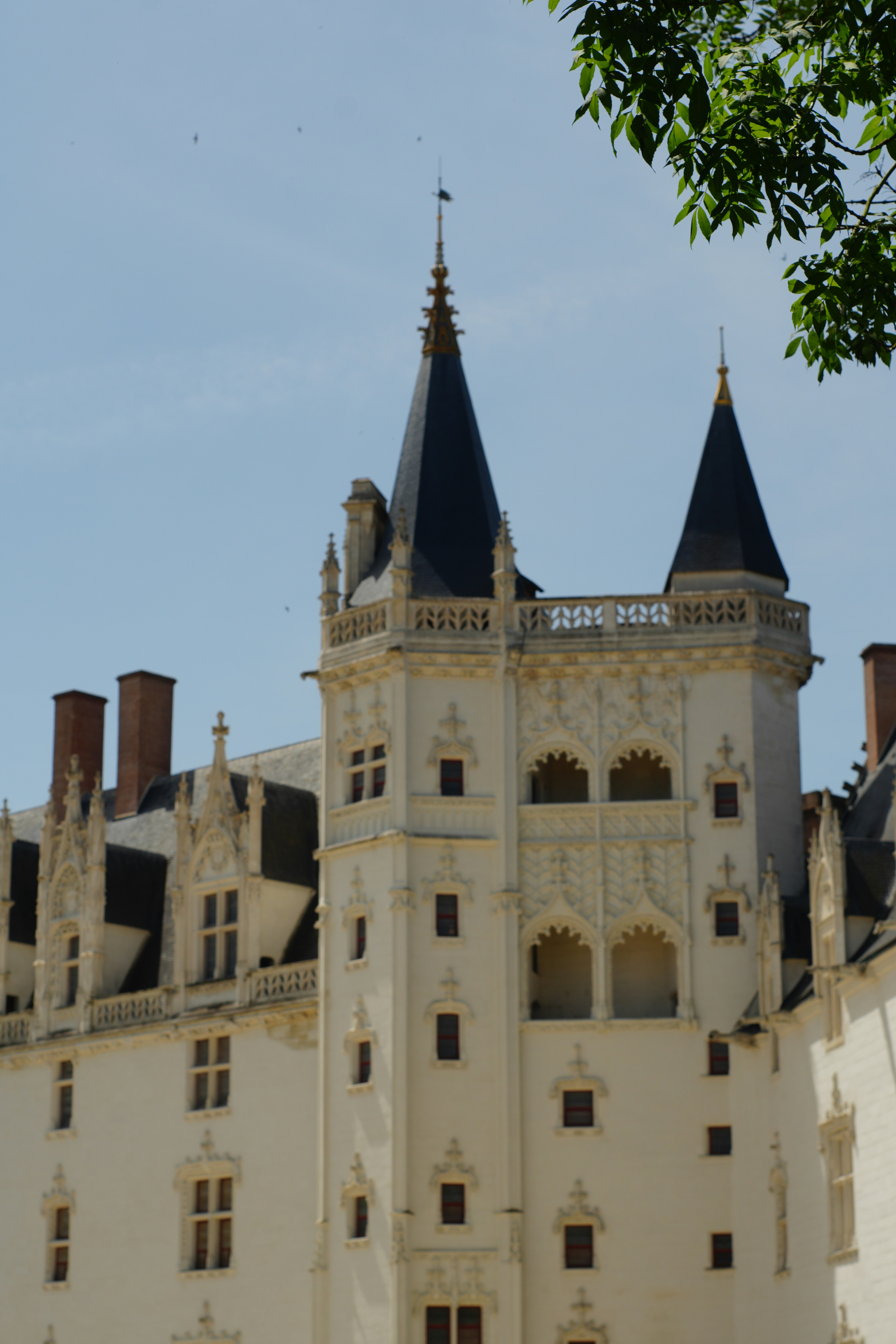 Castle Turrets Rising Above White Facade in Bright Blue Sky