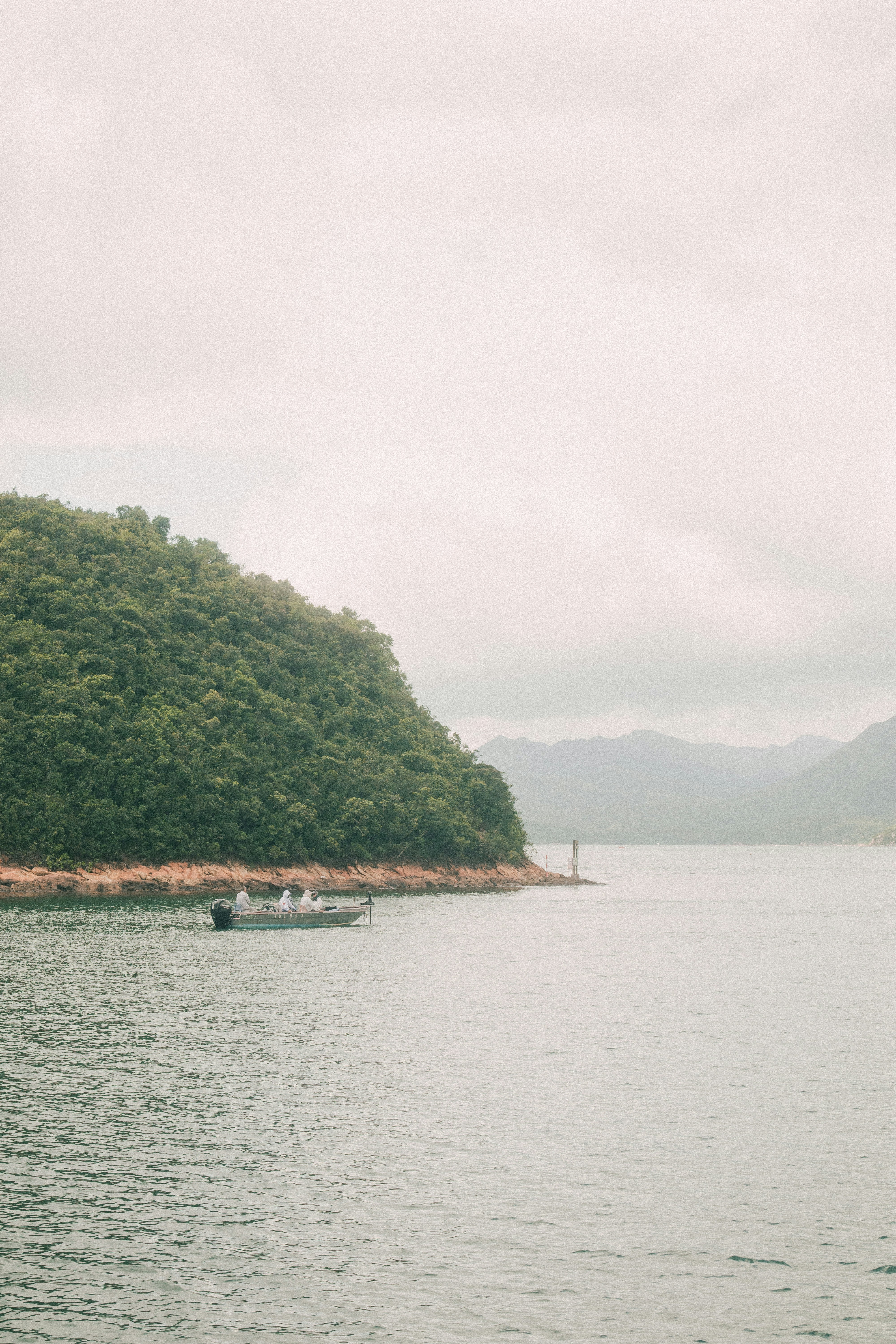 A boat on calm water near a lush green island.