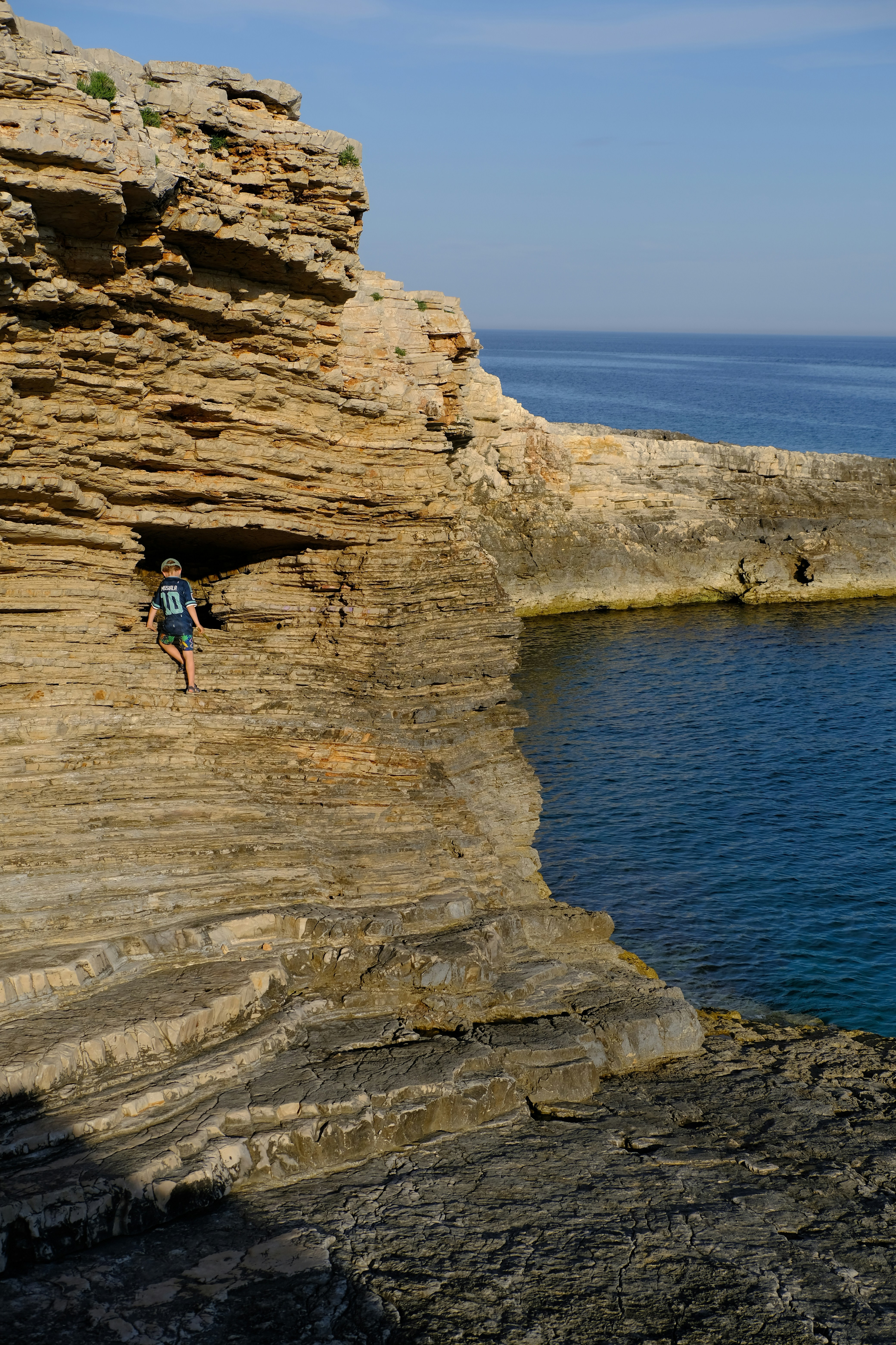 Climber on the Weathered Cliff Edge by a Quiet Sea