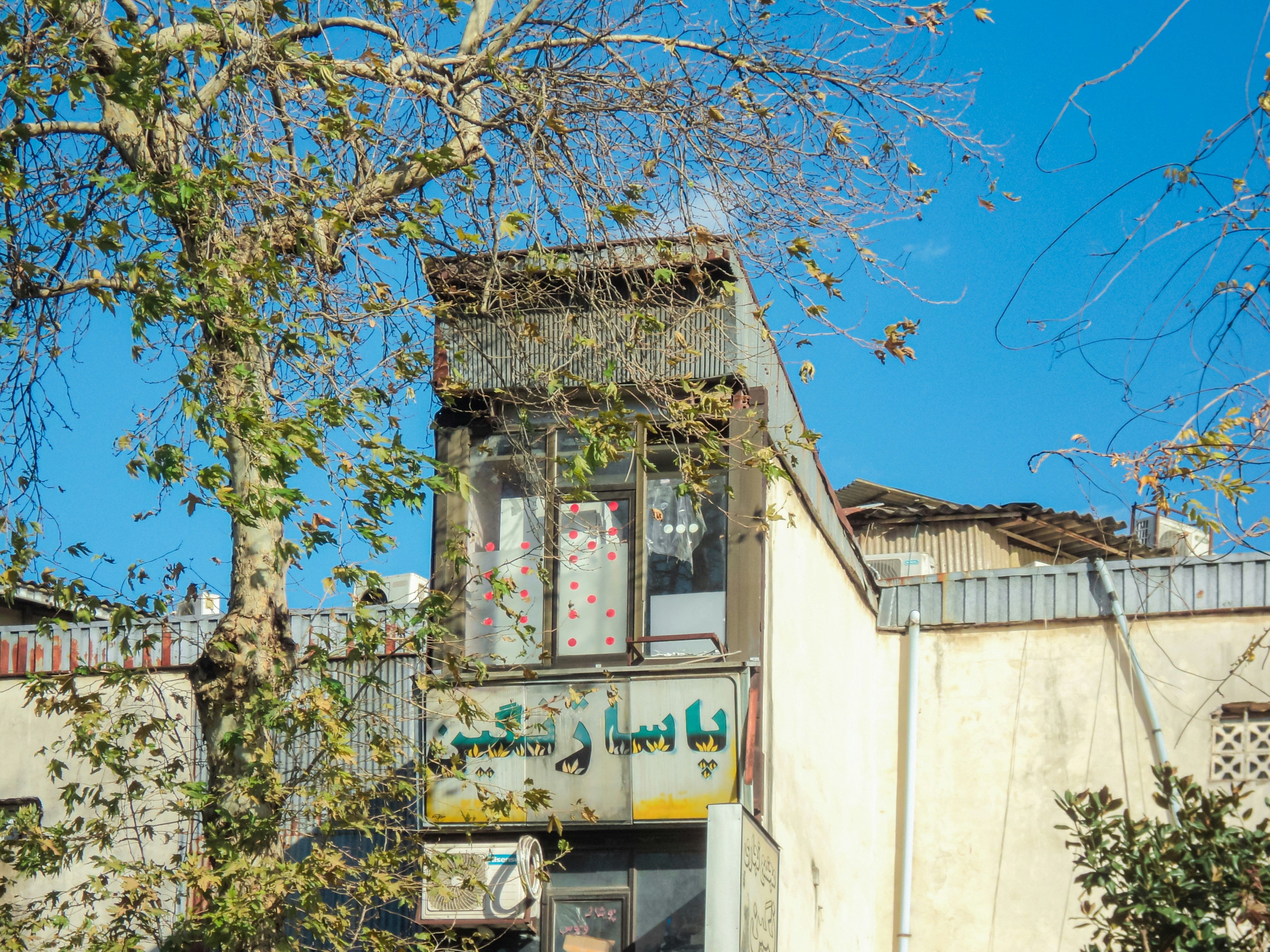 Sunlit storefront atop a weathered building under a clear blue sky