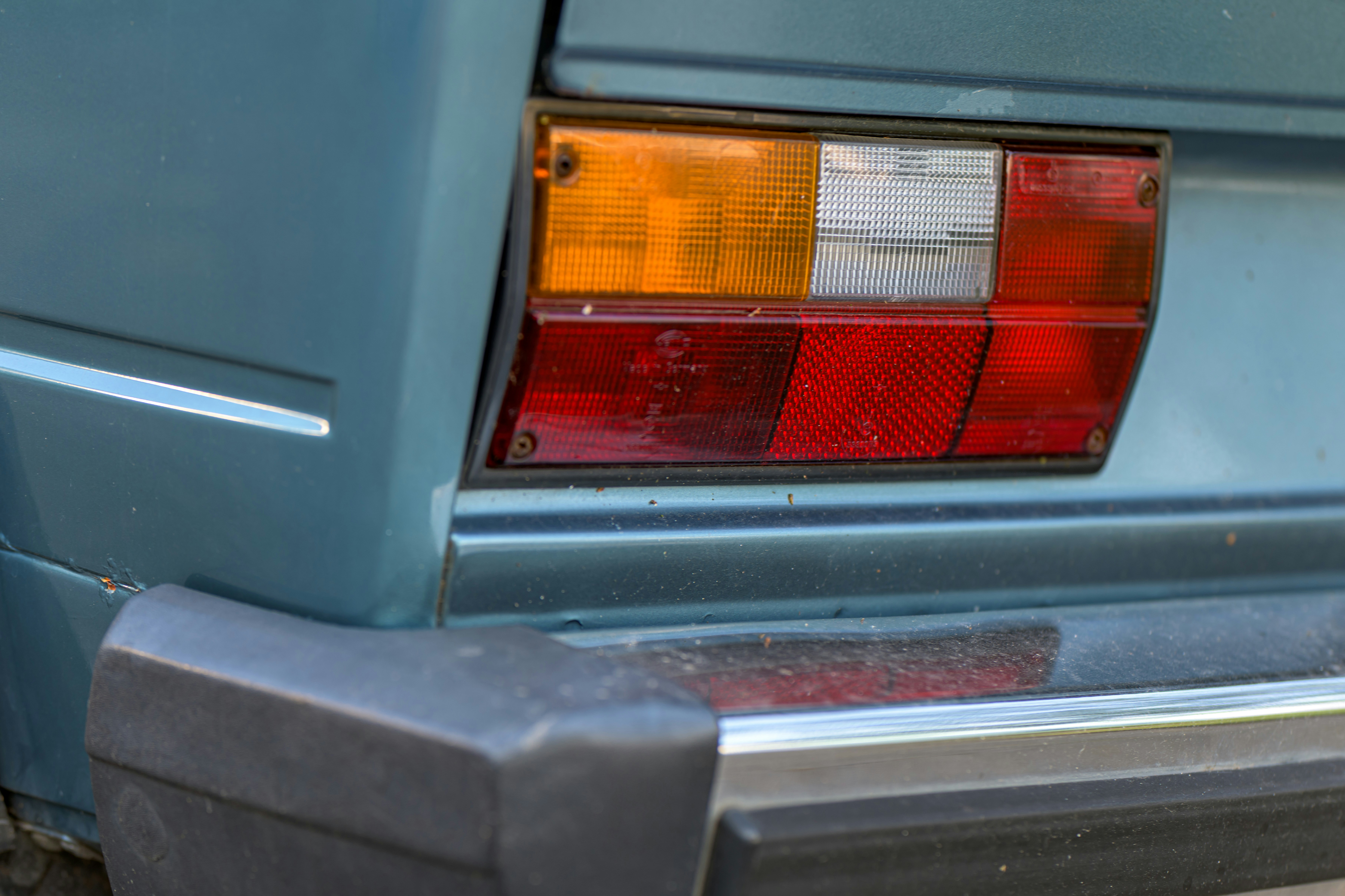 Close-up of a weathered car tail light and bumper showing vintage automotive details
