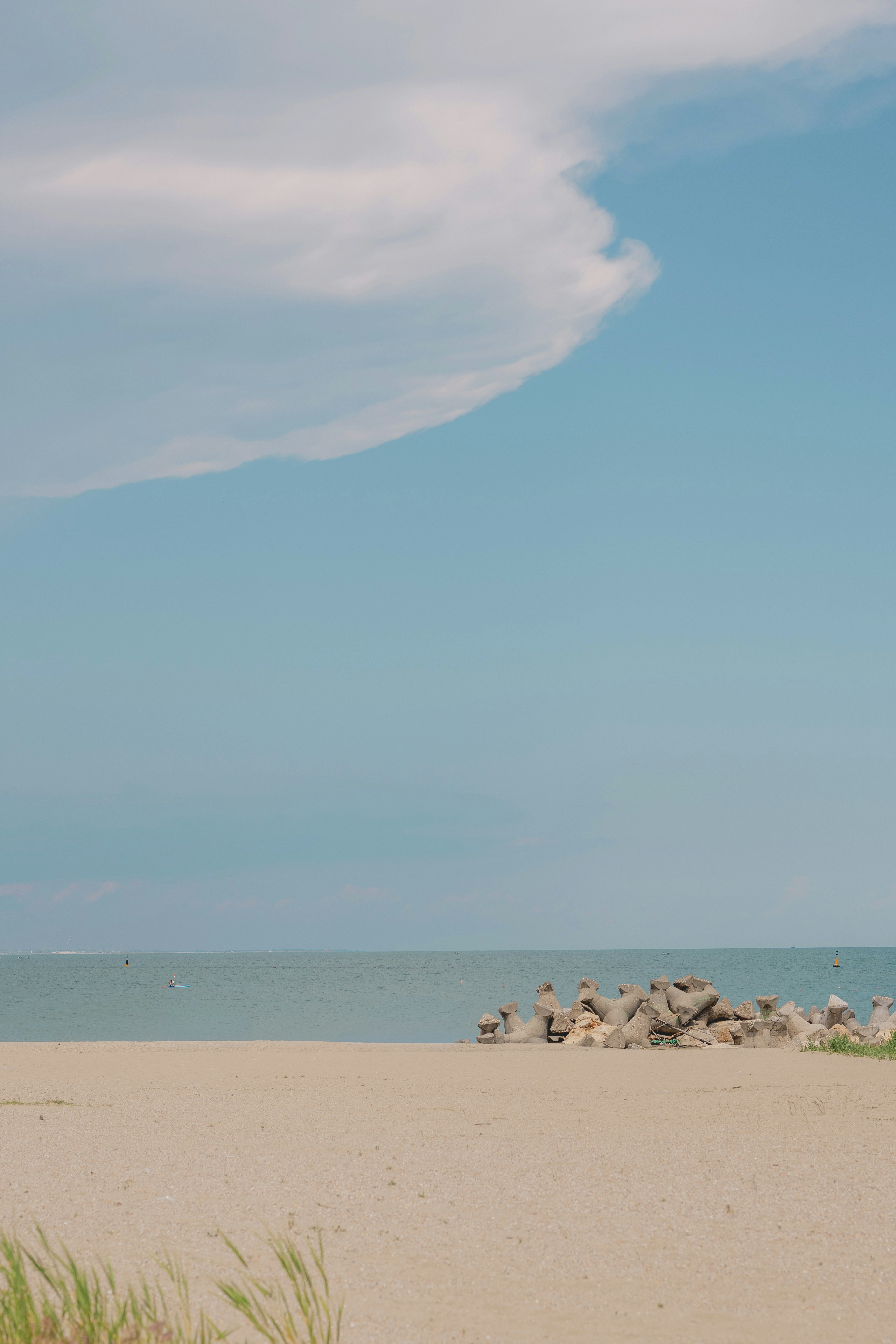 Quiet Horizon: Beach, Sky, and Distant Breakwater
